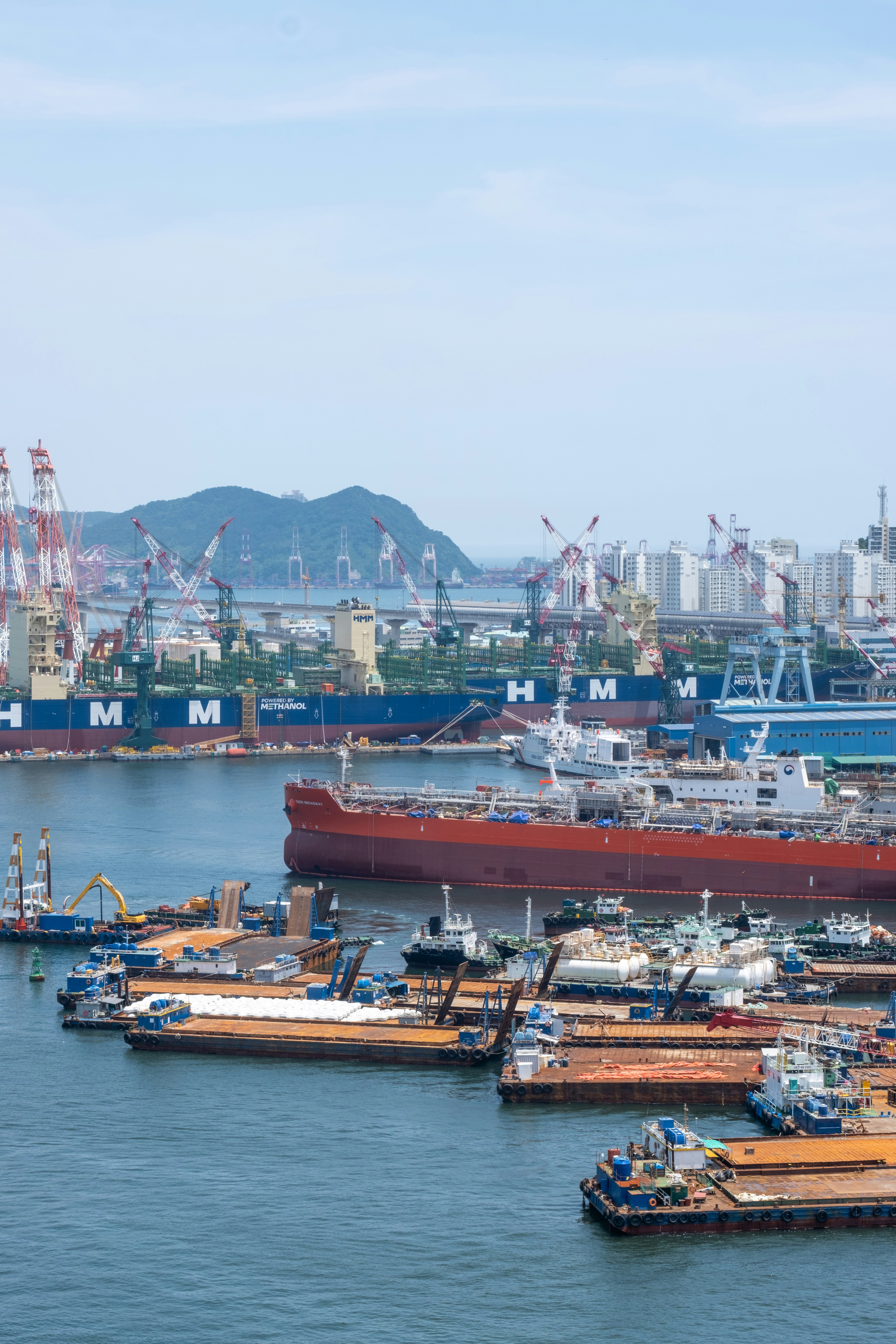 Busy shipyard with ships and cranes under a clear sky