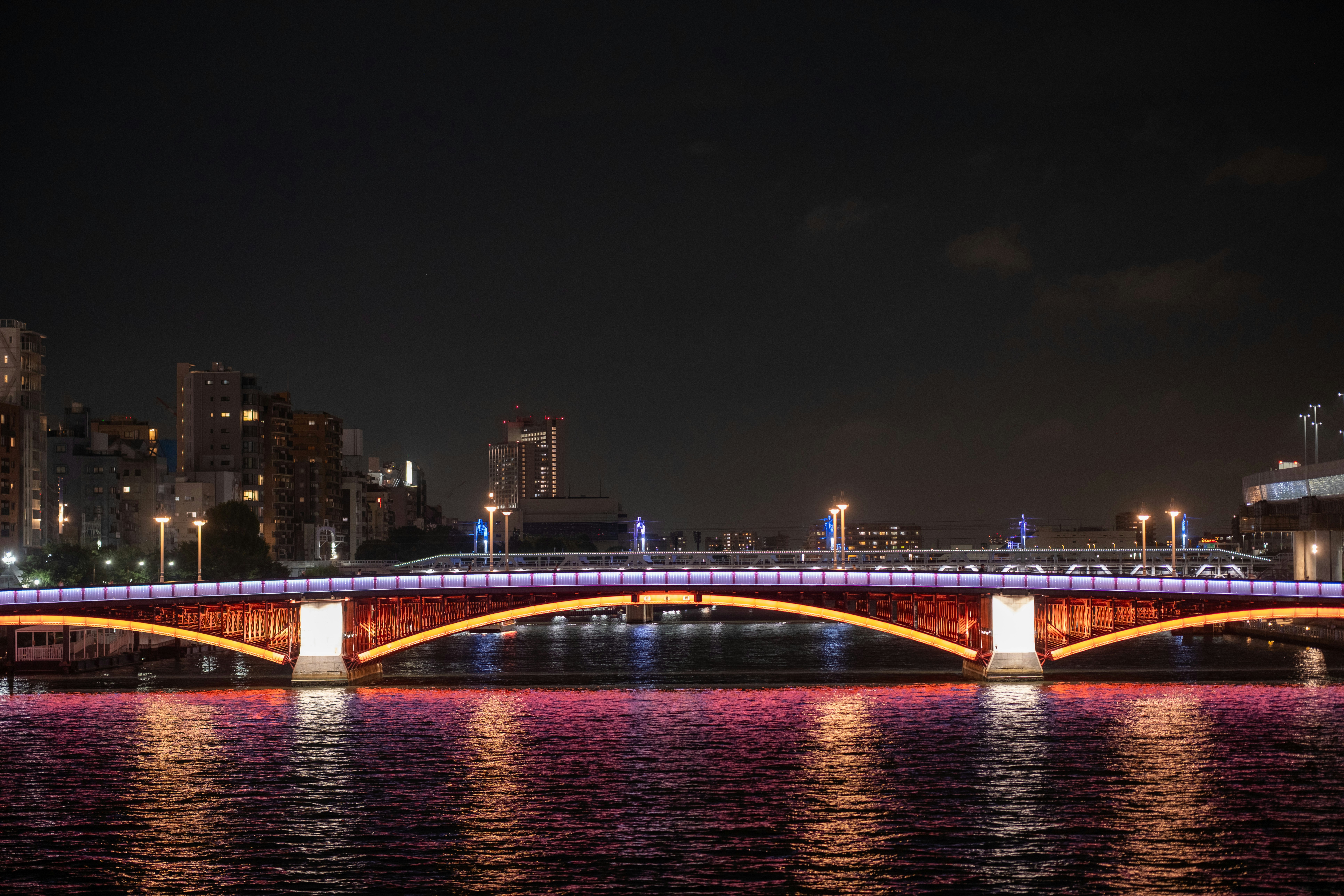 Illuminated bridge over water at night