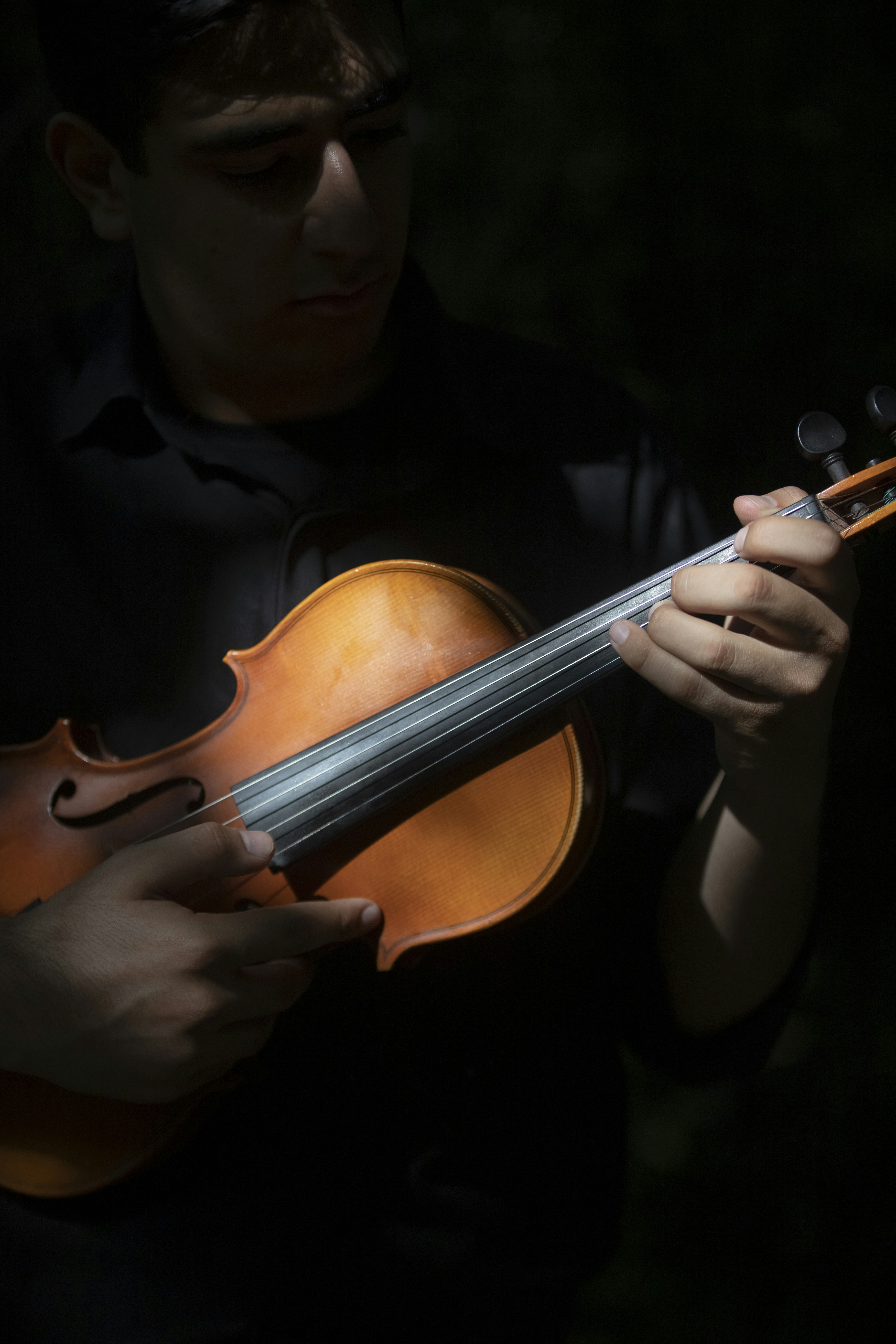 Man playing violin in dramatic lighting