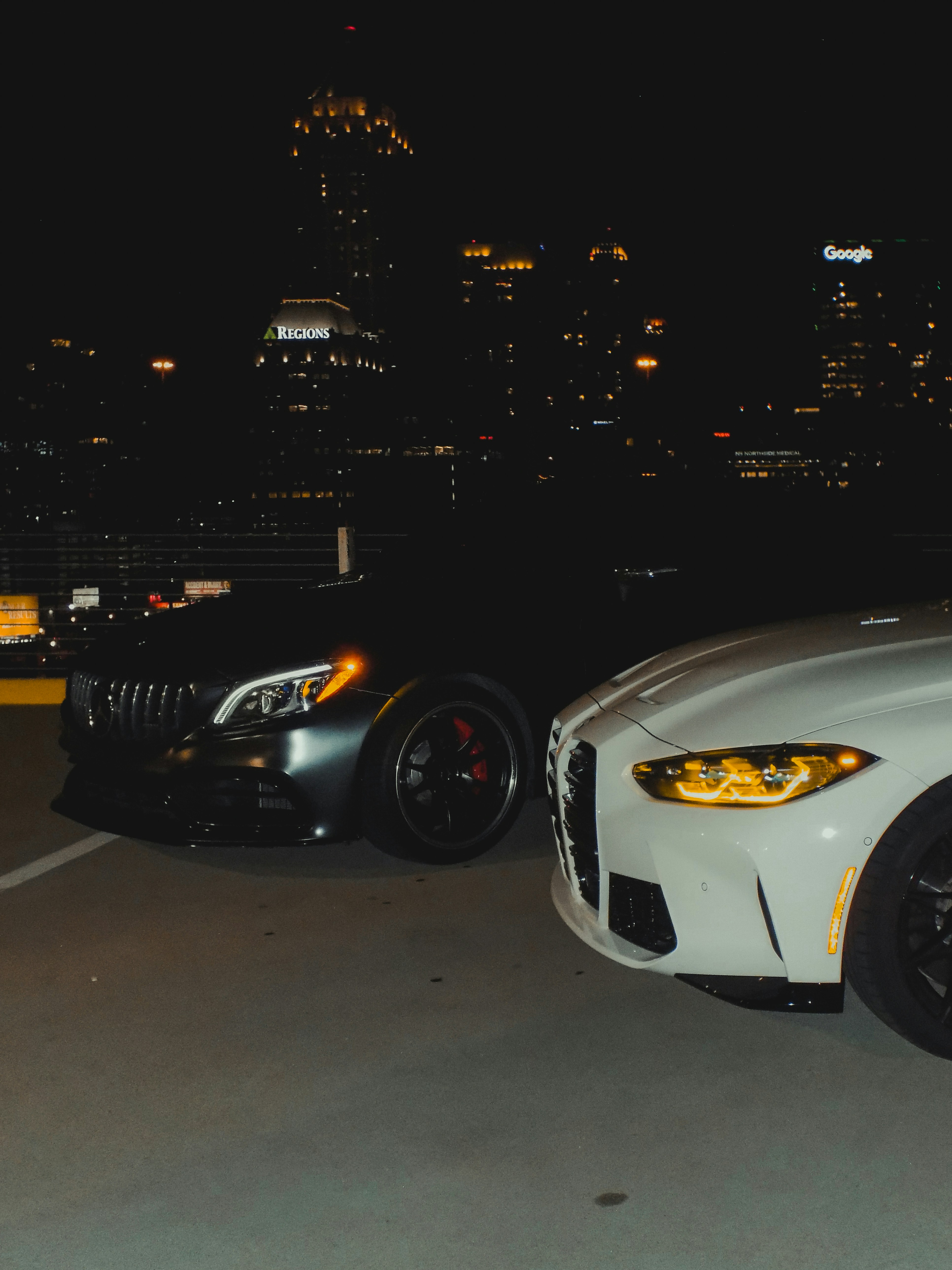 Two luxury cars parked on a rooftop at night.