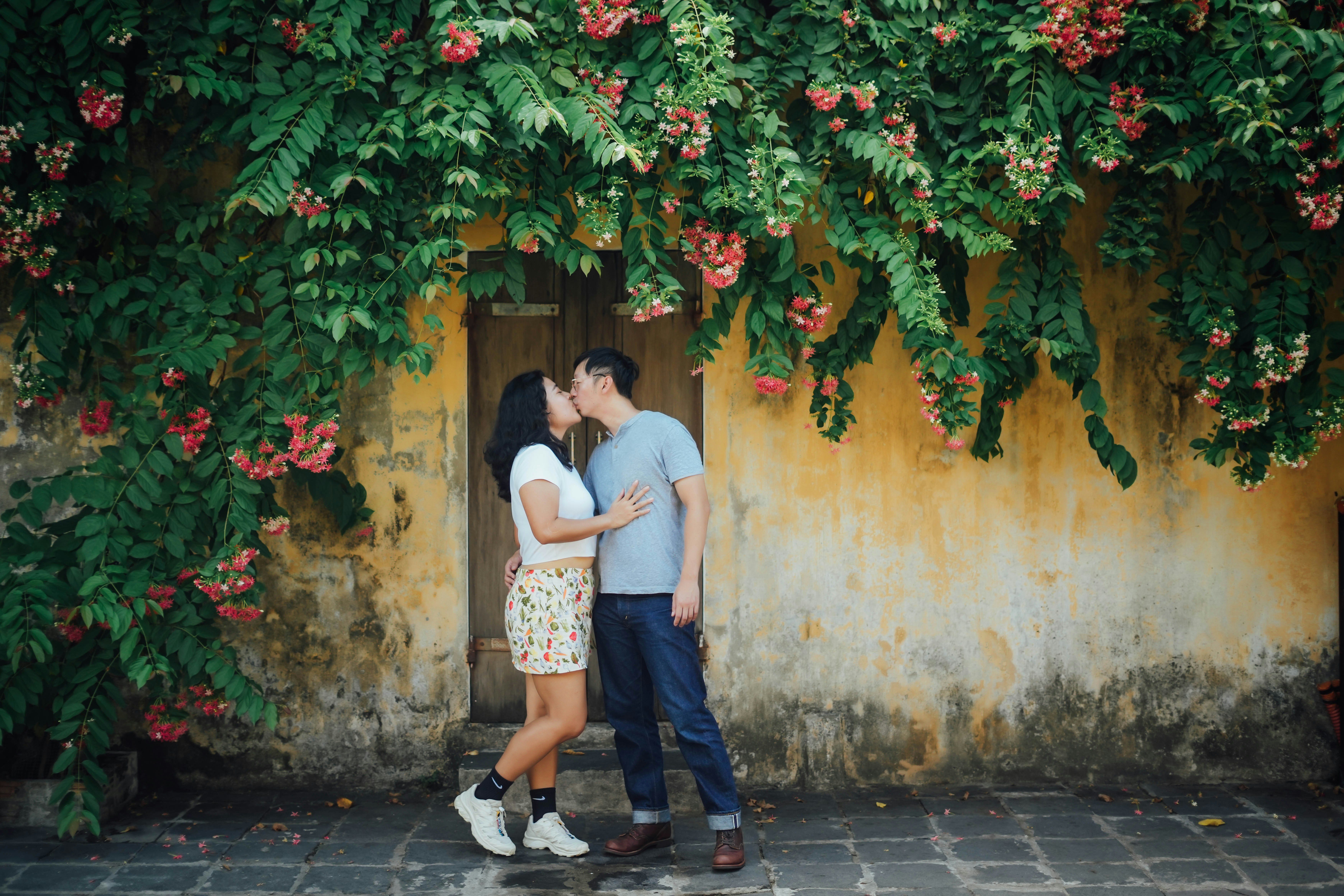 https://fernandesphotography.vn/ | Couple kissing in front of a vine-covered wall