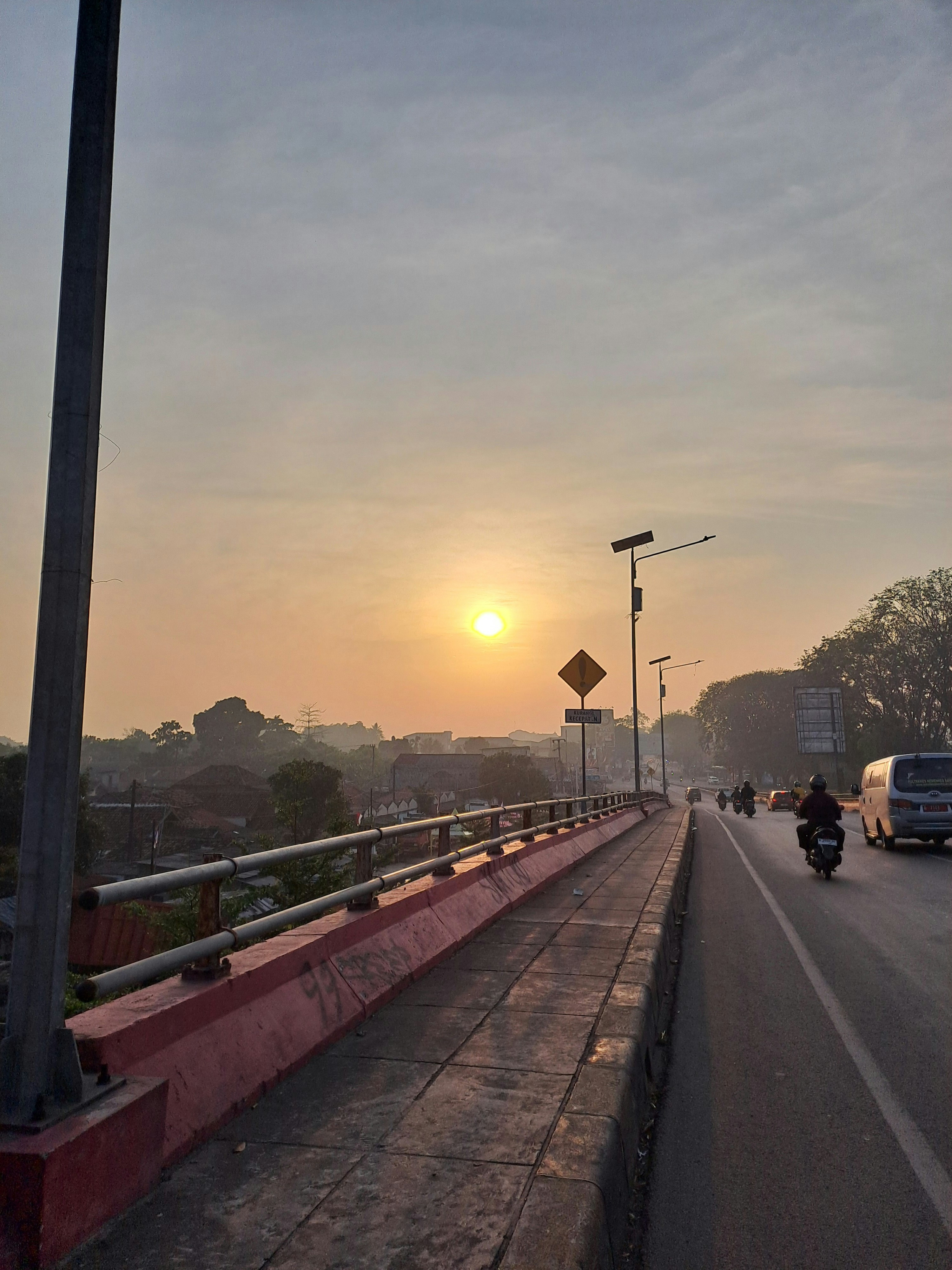 Sunrise over a busy street with a bridge.