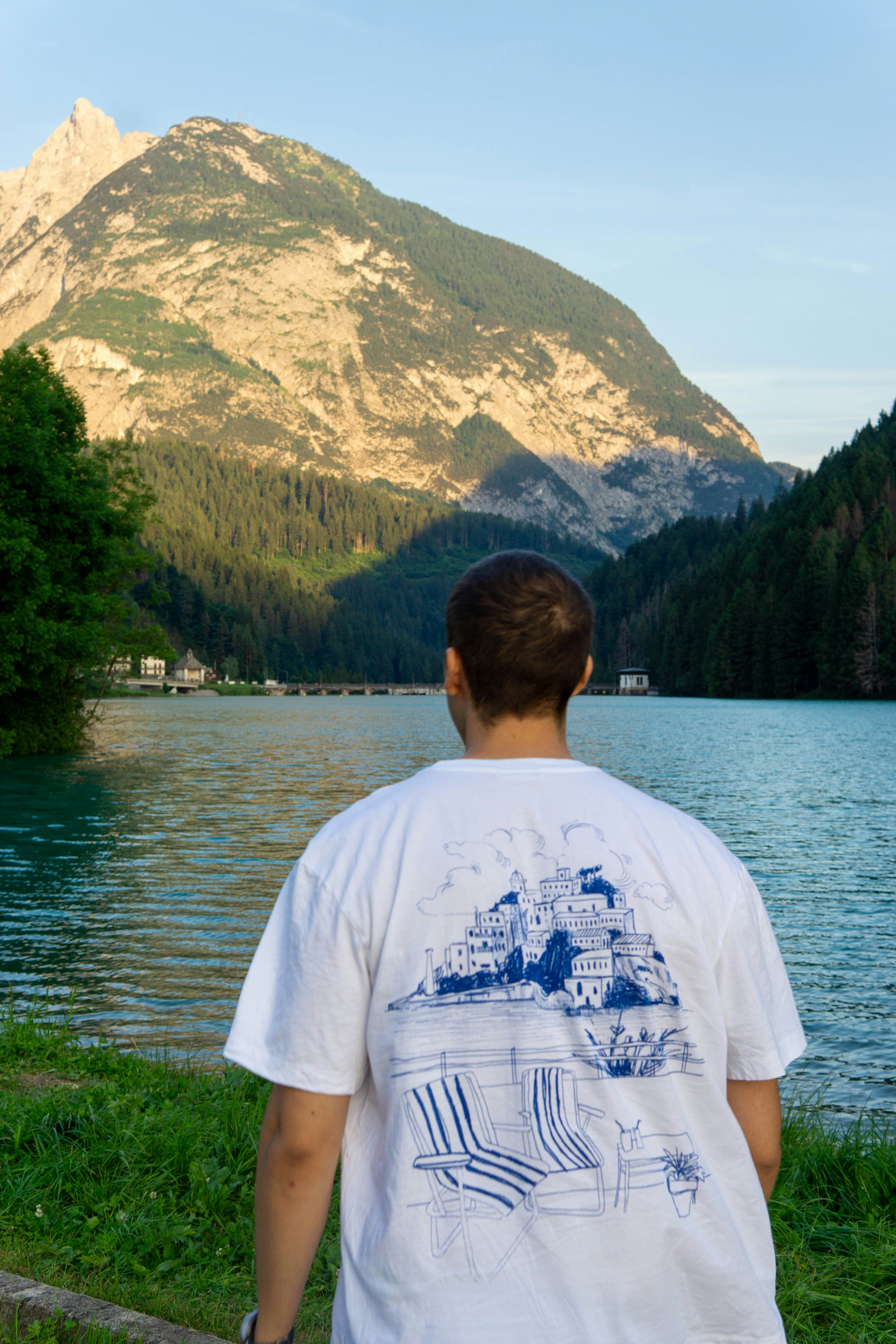 Lakeside Reverie: A Back-Turned Traveler Framed by Alpine Peaks