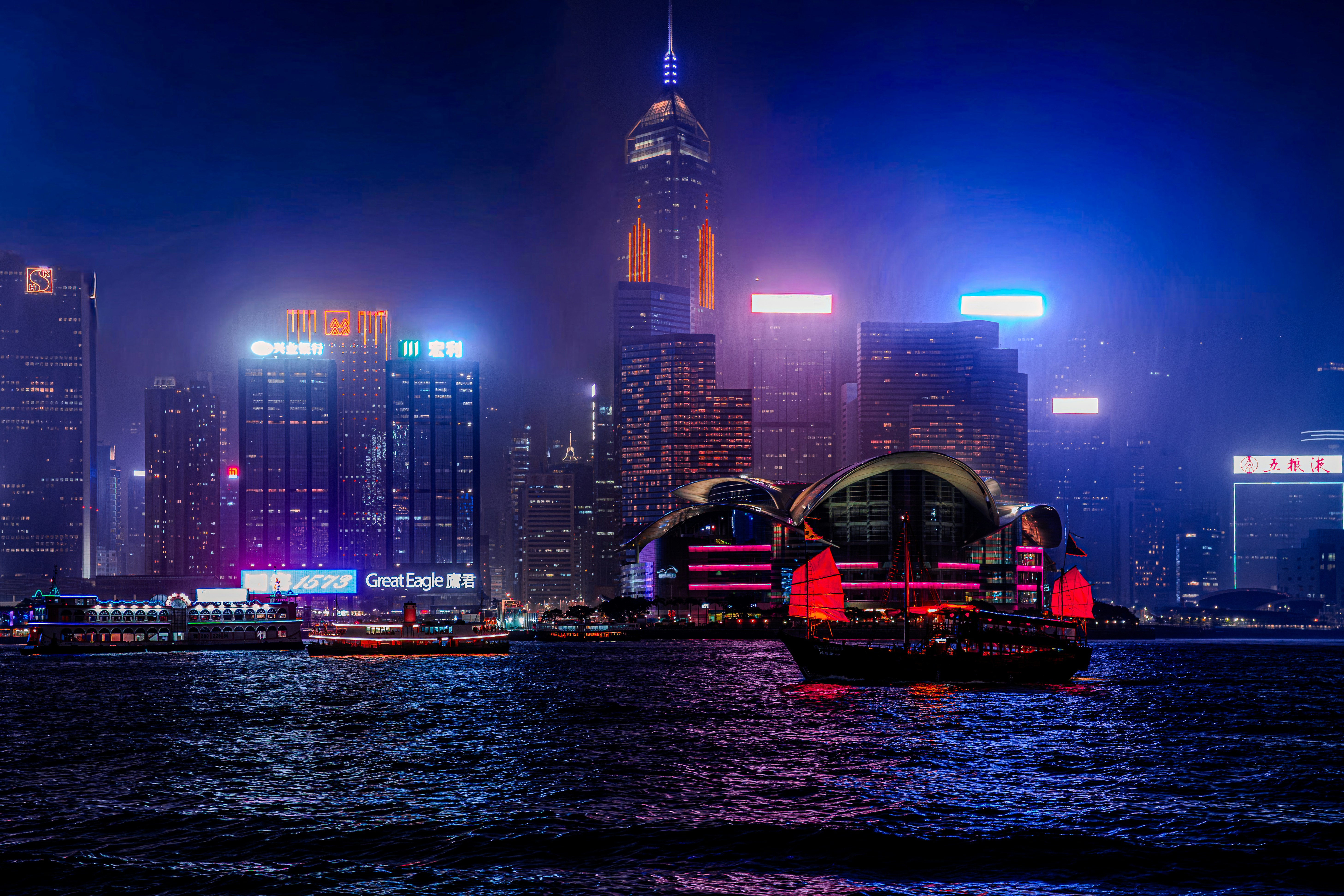 Vibrant cityscape with illuminated skyscrapers and boats at night