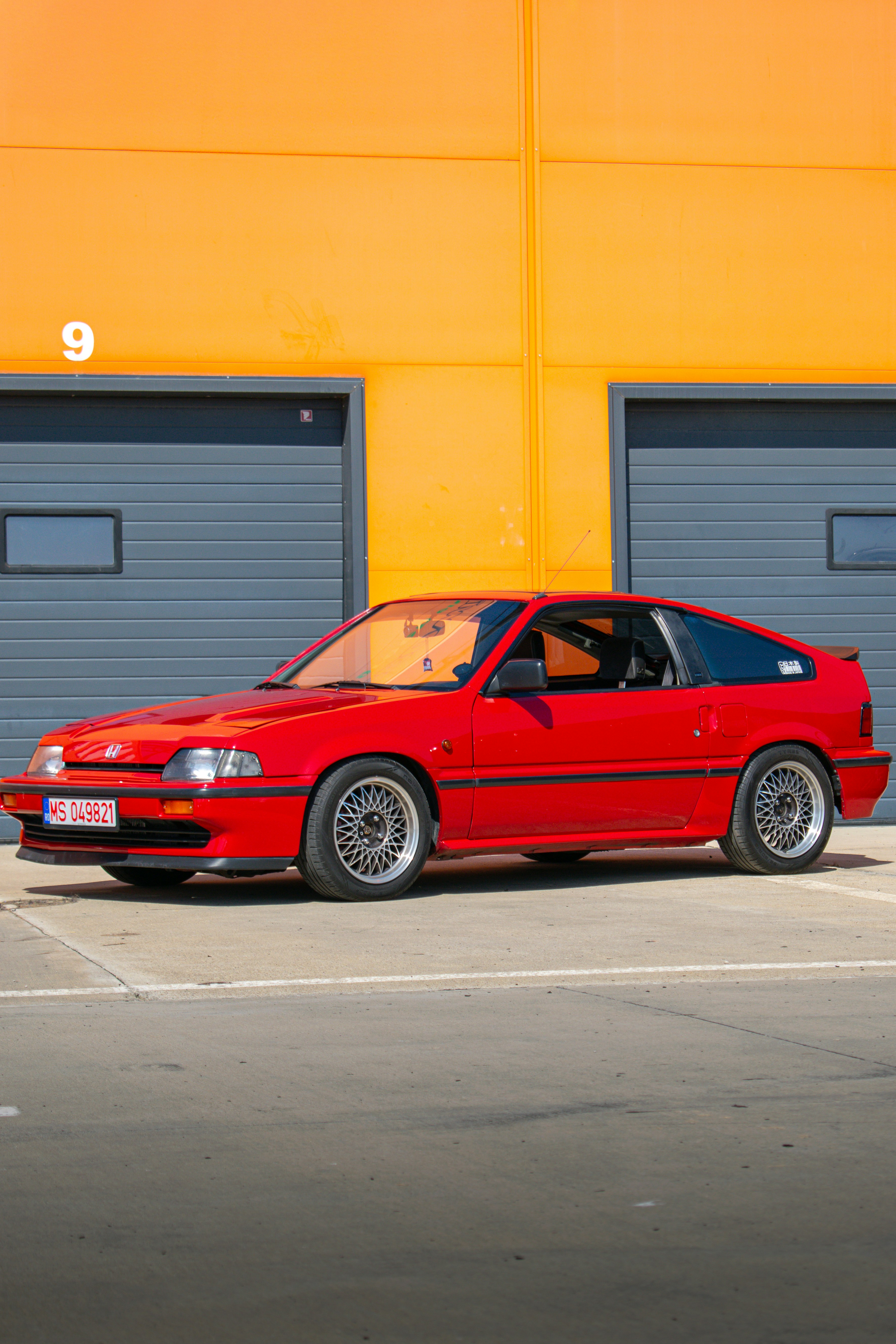 Red sports car parked in front of orange building