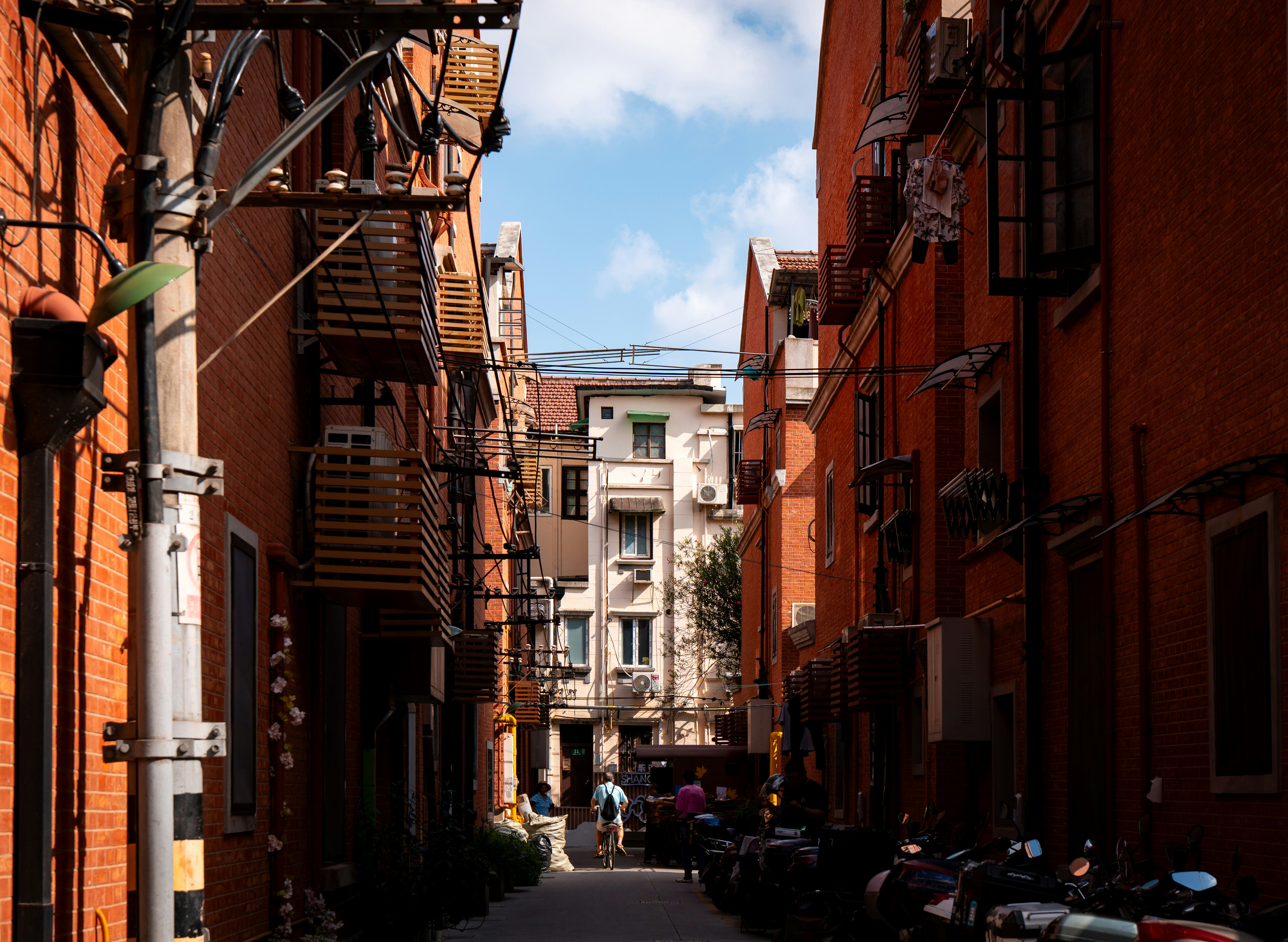 Narrow alleyway between brick buildings with parked motorcycles.