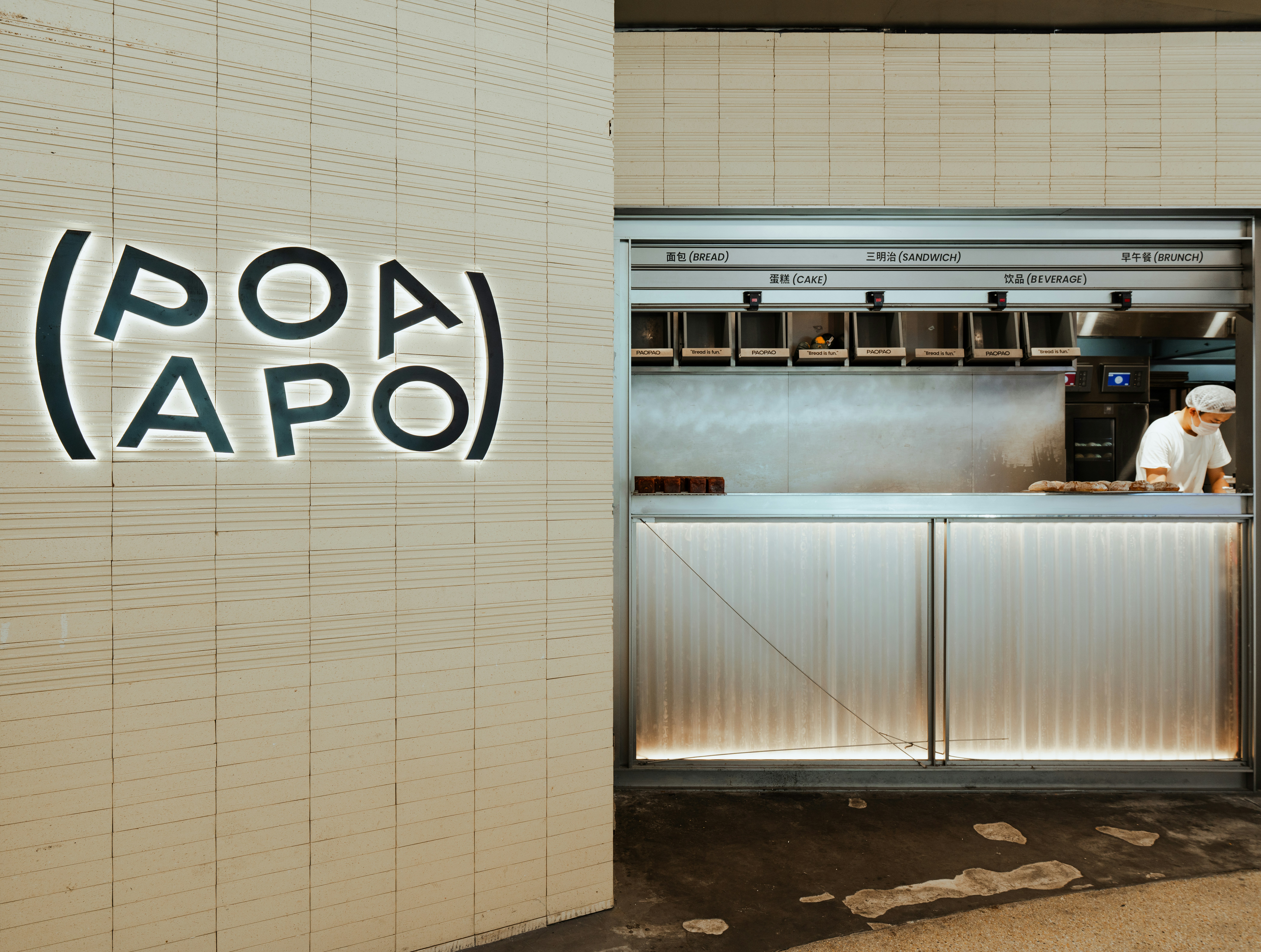 Modern restaurant interior with illuminated logo and tiled facade.