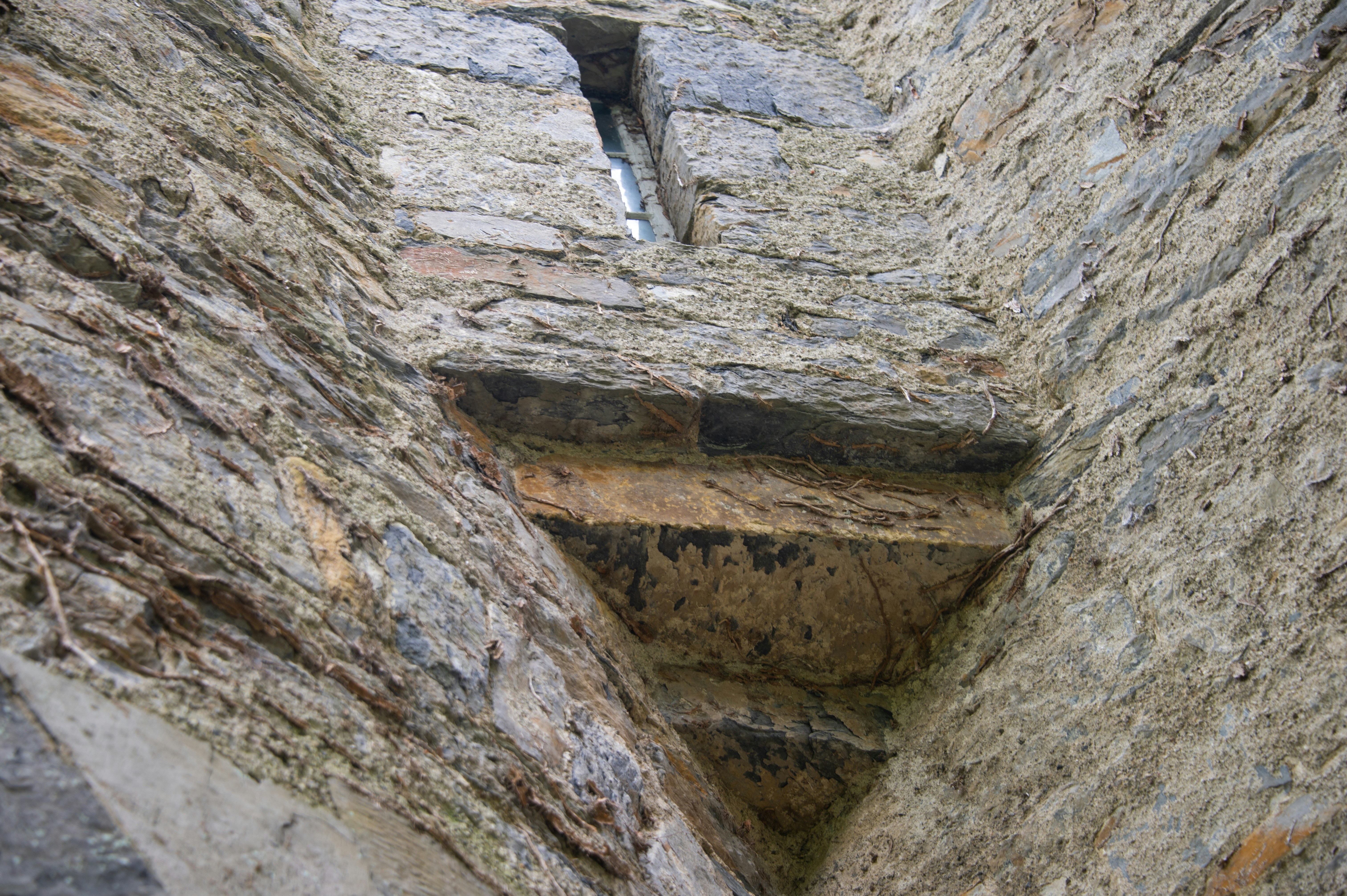 A view from below of a small rectangular window in a castle | Stone wall with a narrow opening