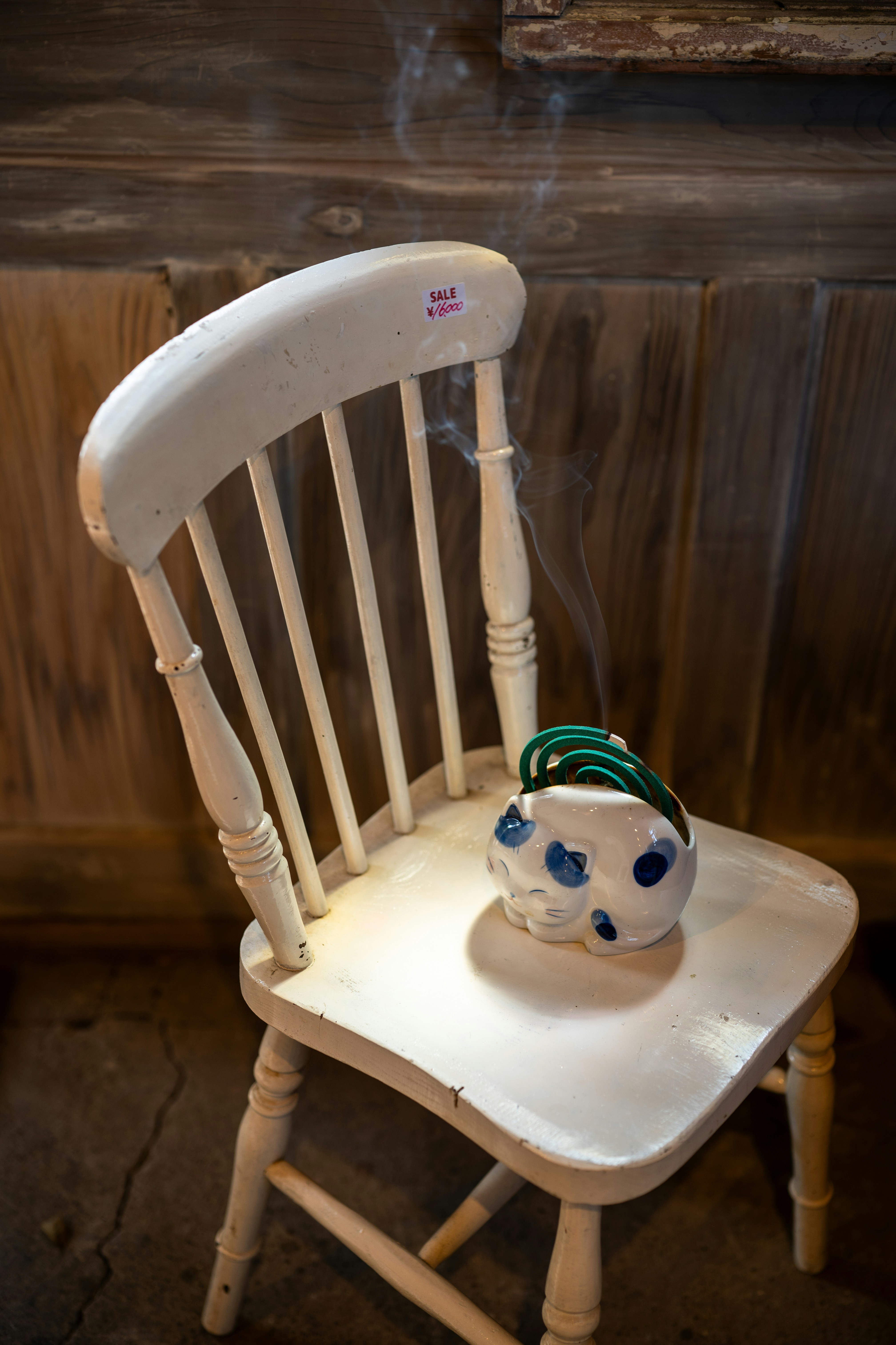 White chair with incense burning in skull holder.