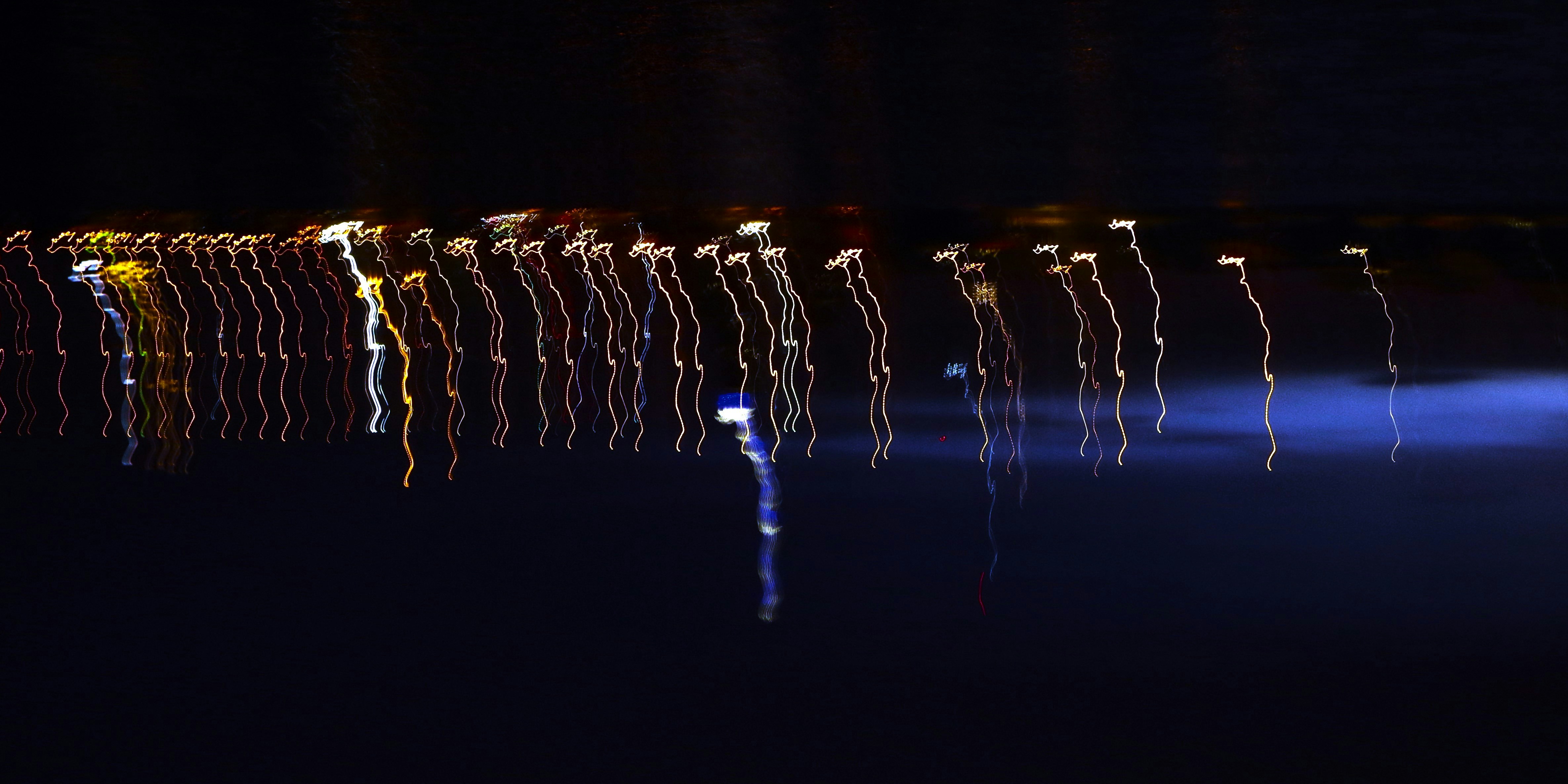 Neon Ribbon Cascade Along a Moonless Waterfront