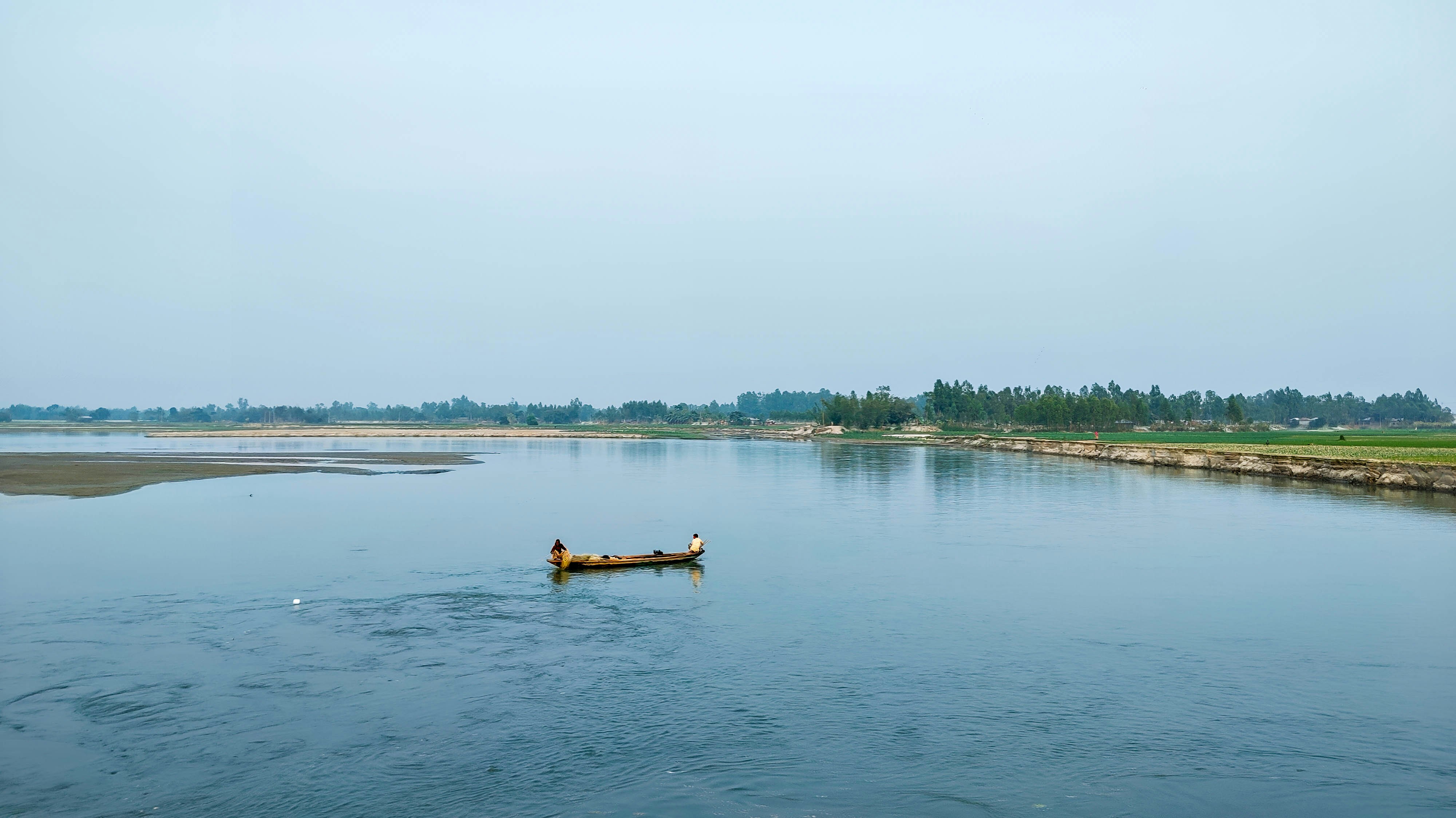 Boat on the Teesta River at Mahipur, Rangpur | Two people in a boat on a wide river
