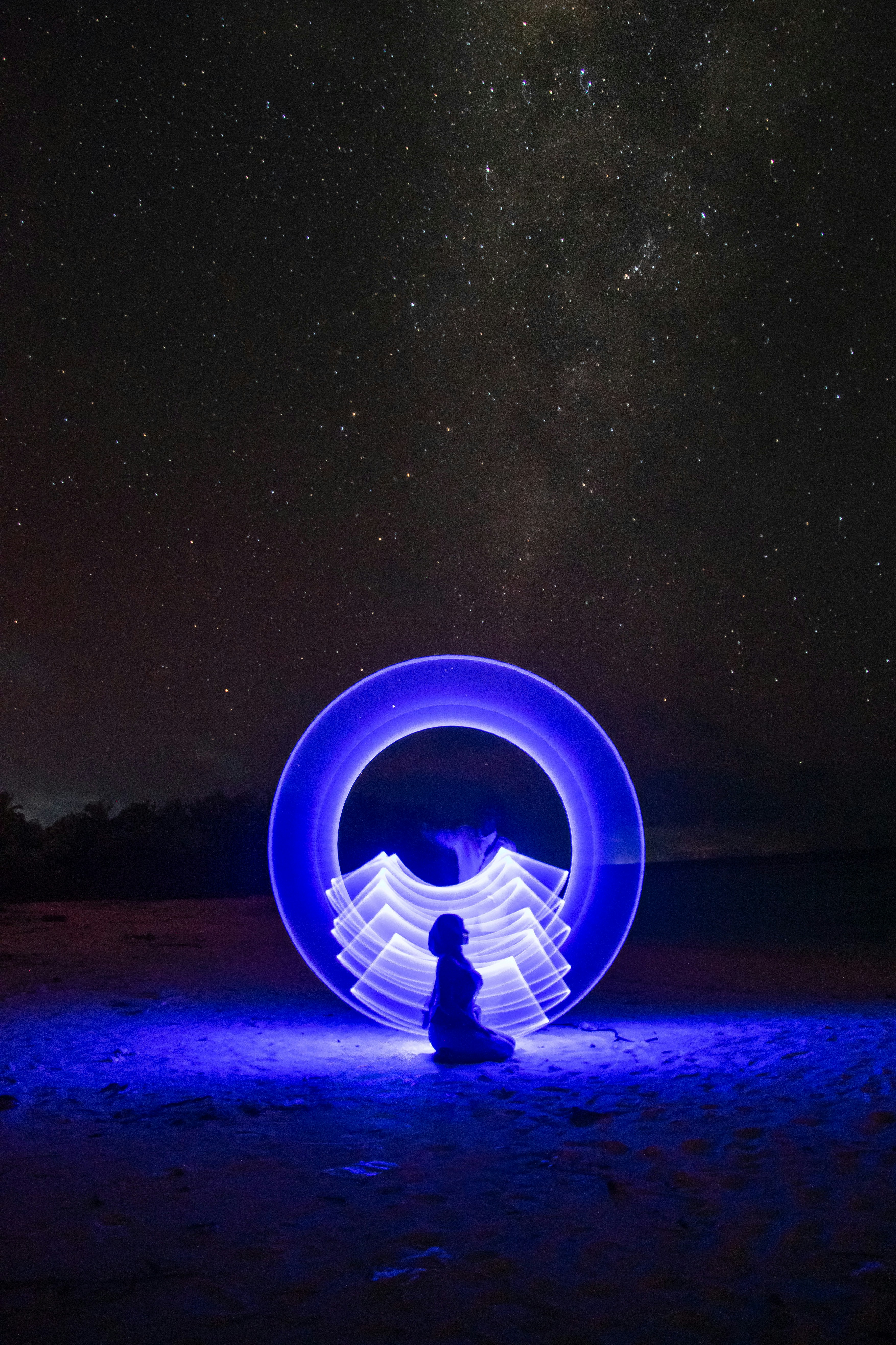 Person sitting inside a glowing blue circle under stars