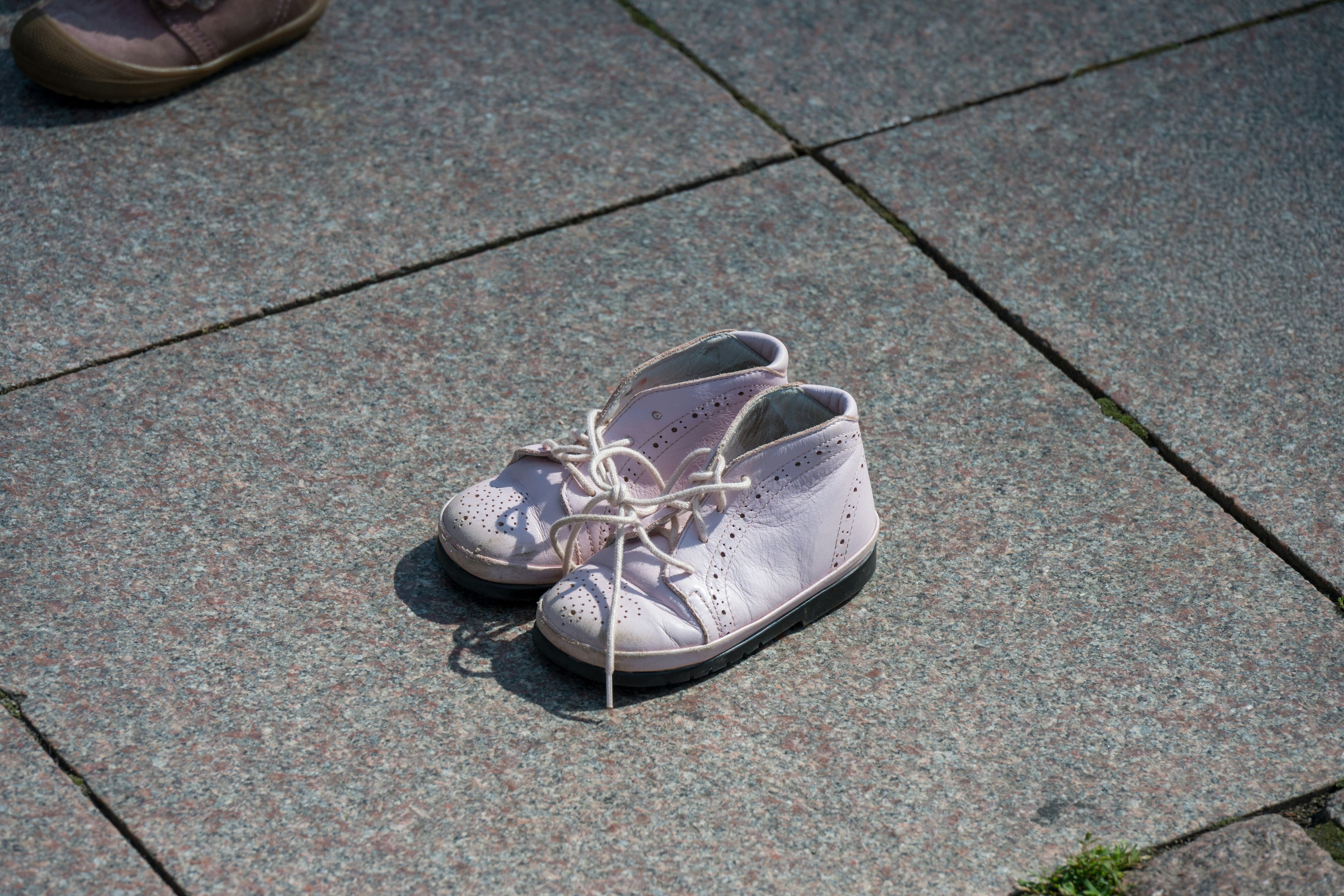 Little Boots on a Sunlit Tile: A Pair of White Shoes on a Quiet Step
