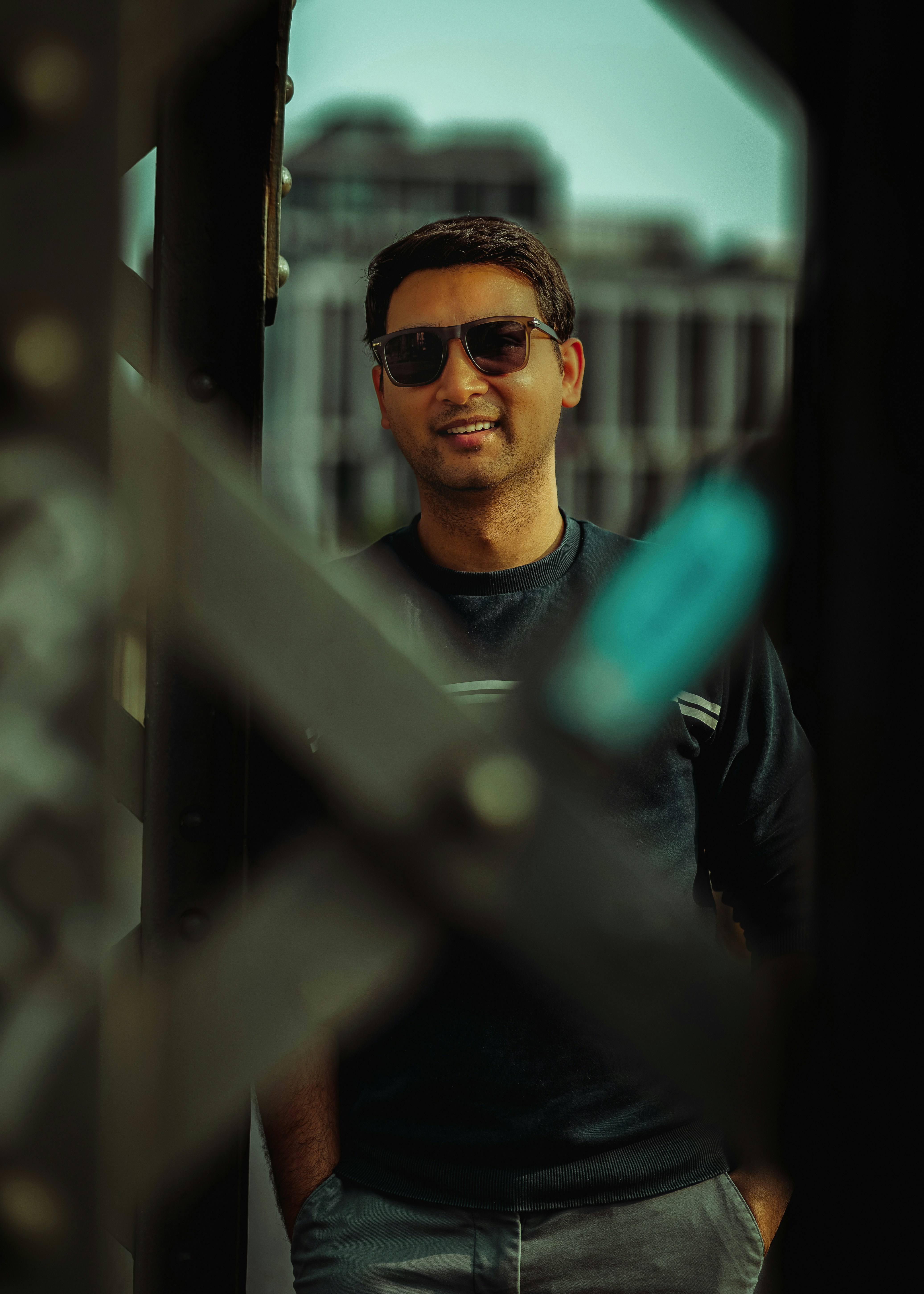 Man in sunglasses smiles behind a metal structure