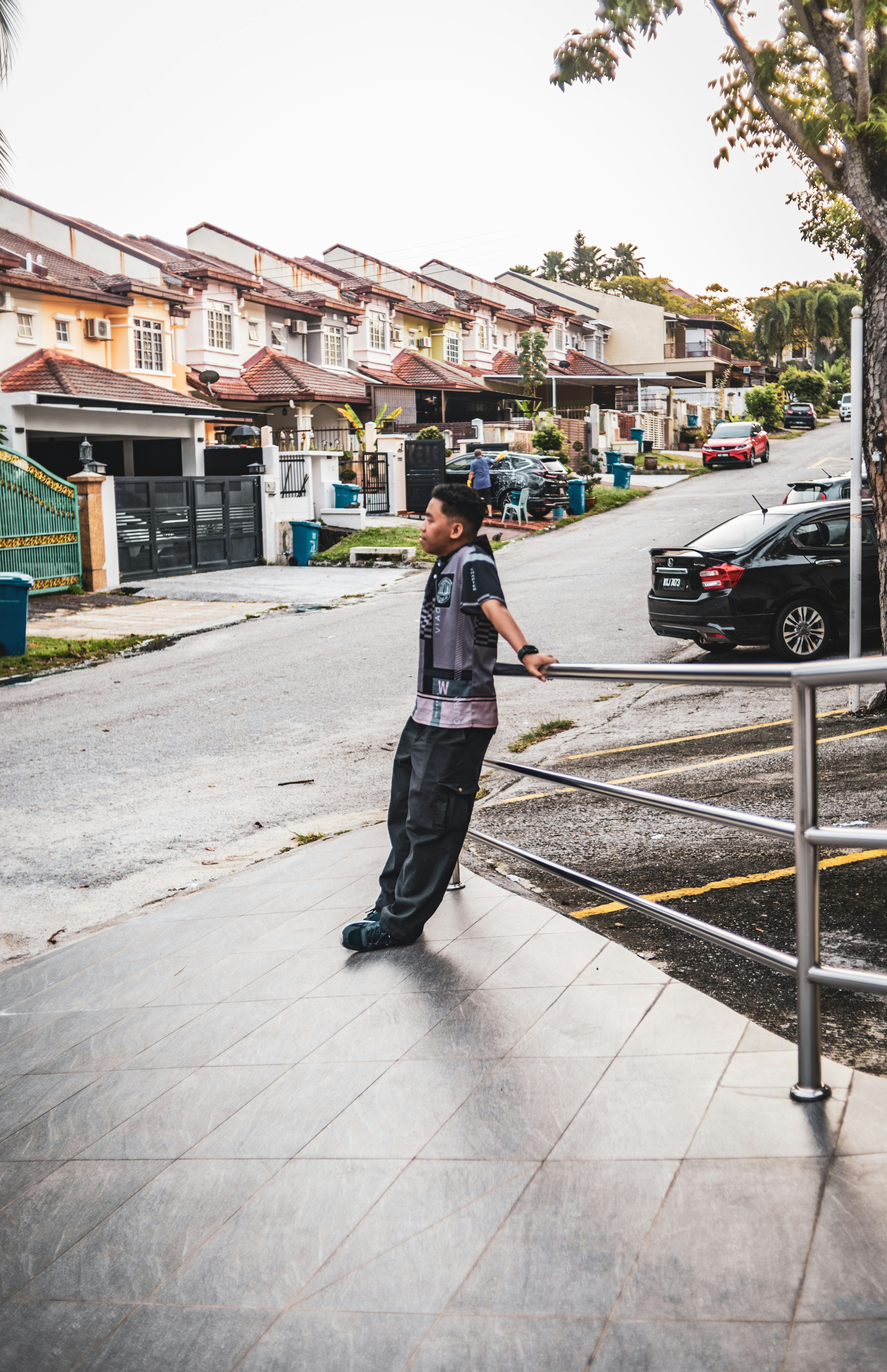 Young man leaning on railing in residential neighborhood