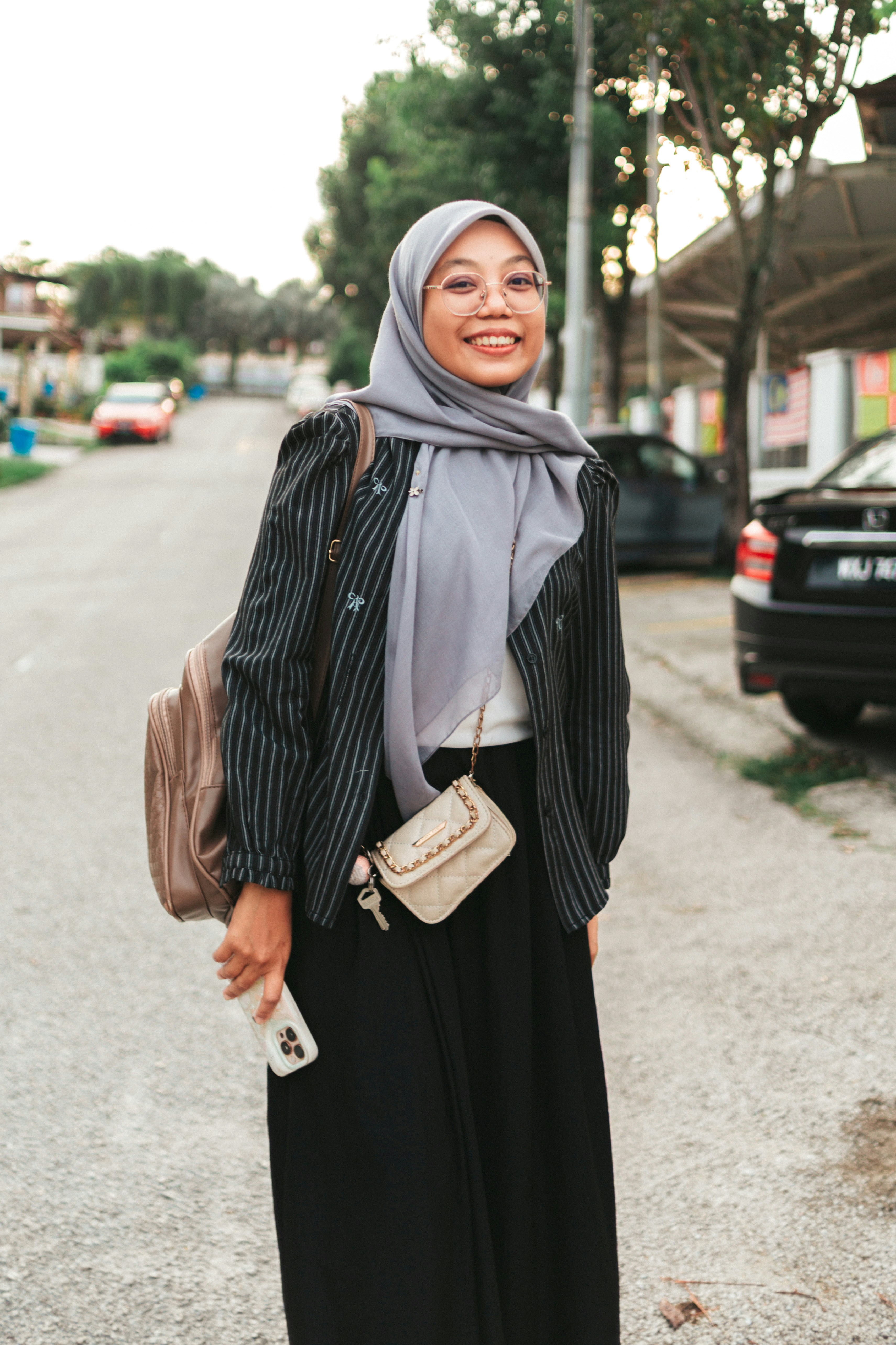 Bright Street Portrait: A Hijab-Wearing Traveler Radiates Confidence on a Quiet Road