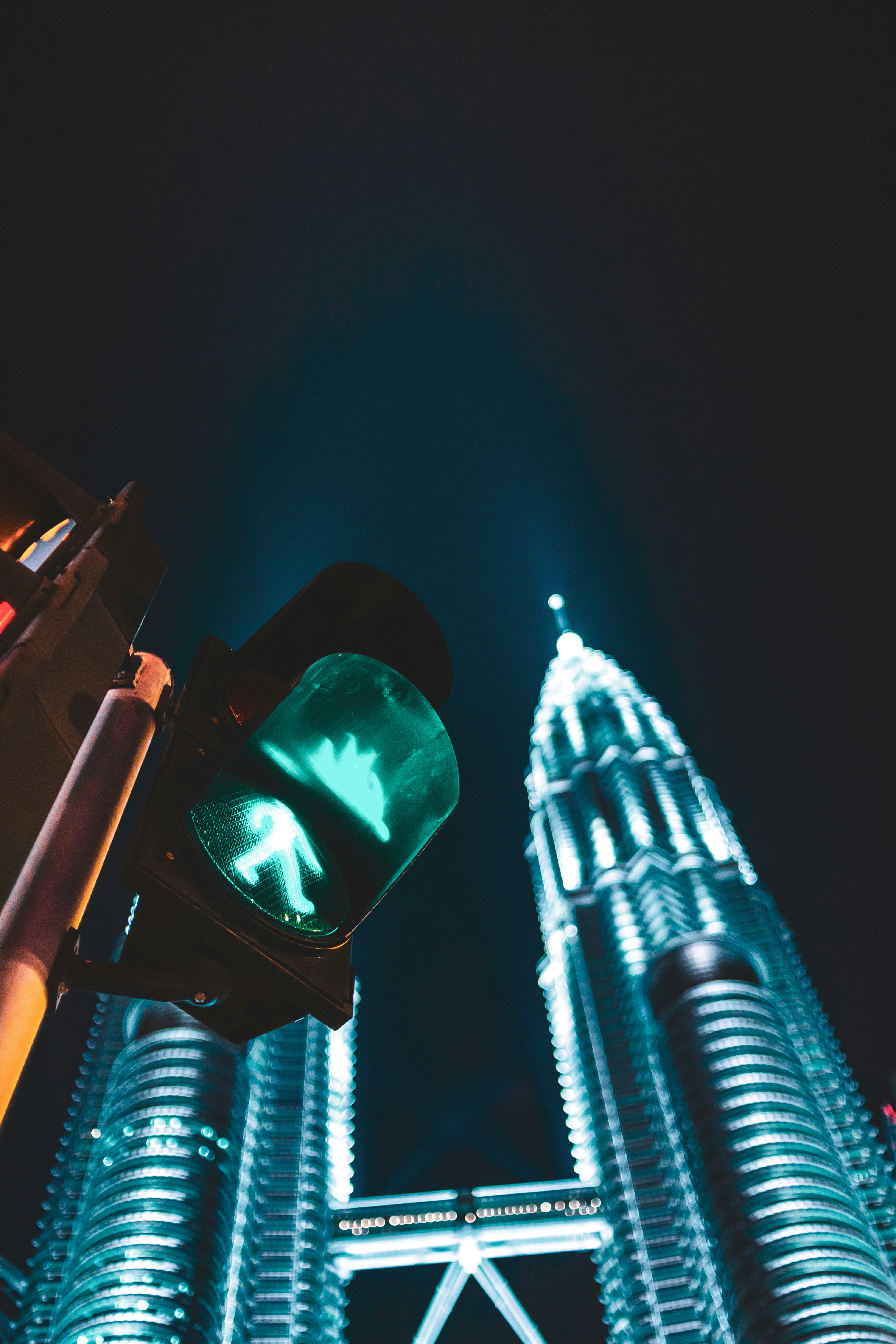 Green pedestrian signal with illuminated towers at night