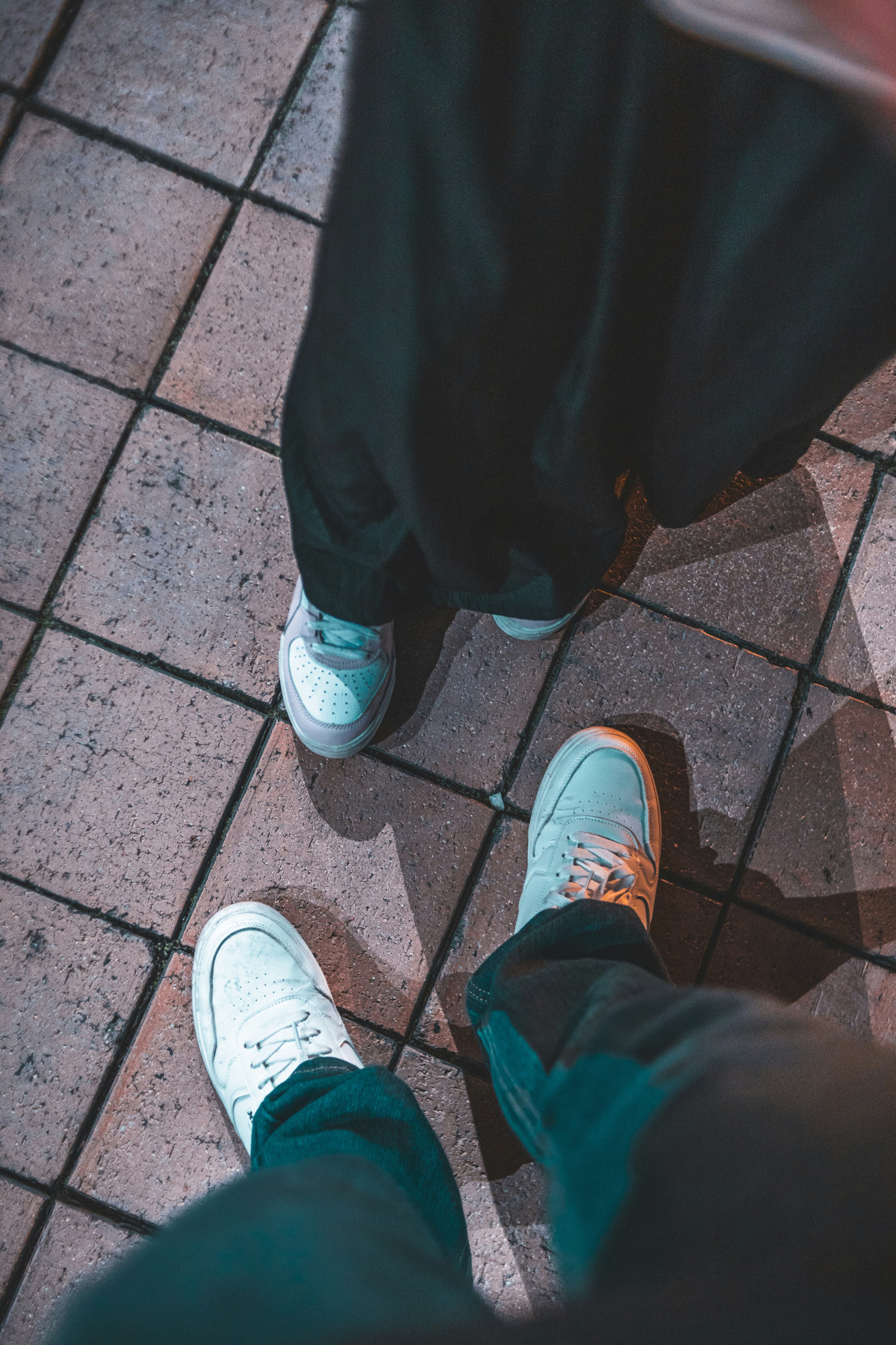 Two people standing on a tiled surface