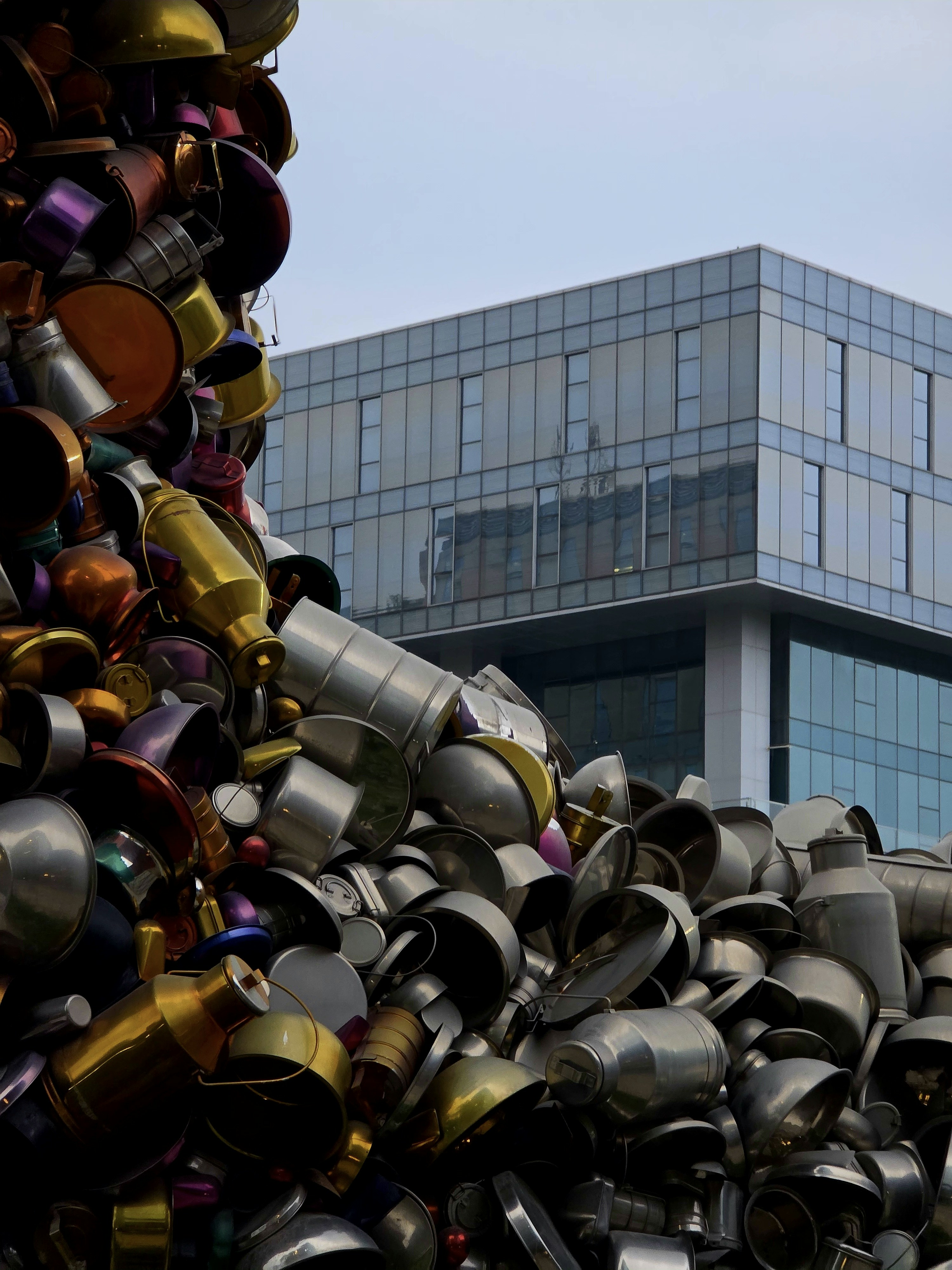 Architecture + Art | Pile of metal pots and pans with modern building
