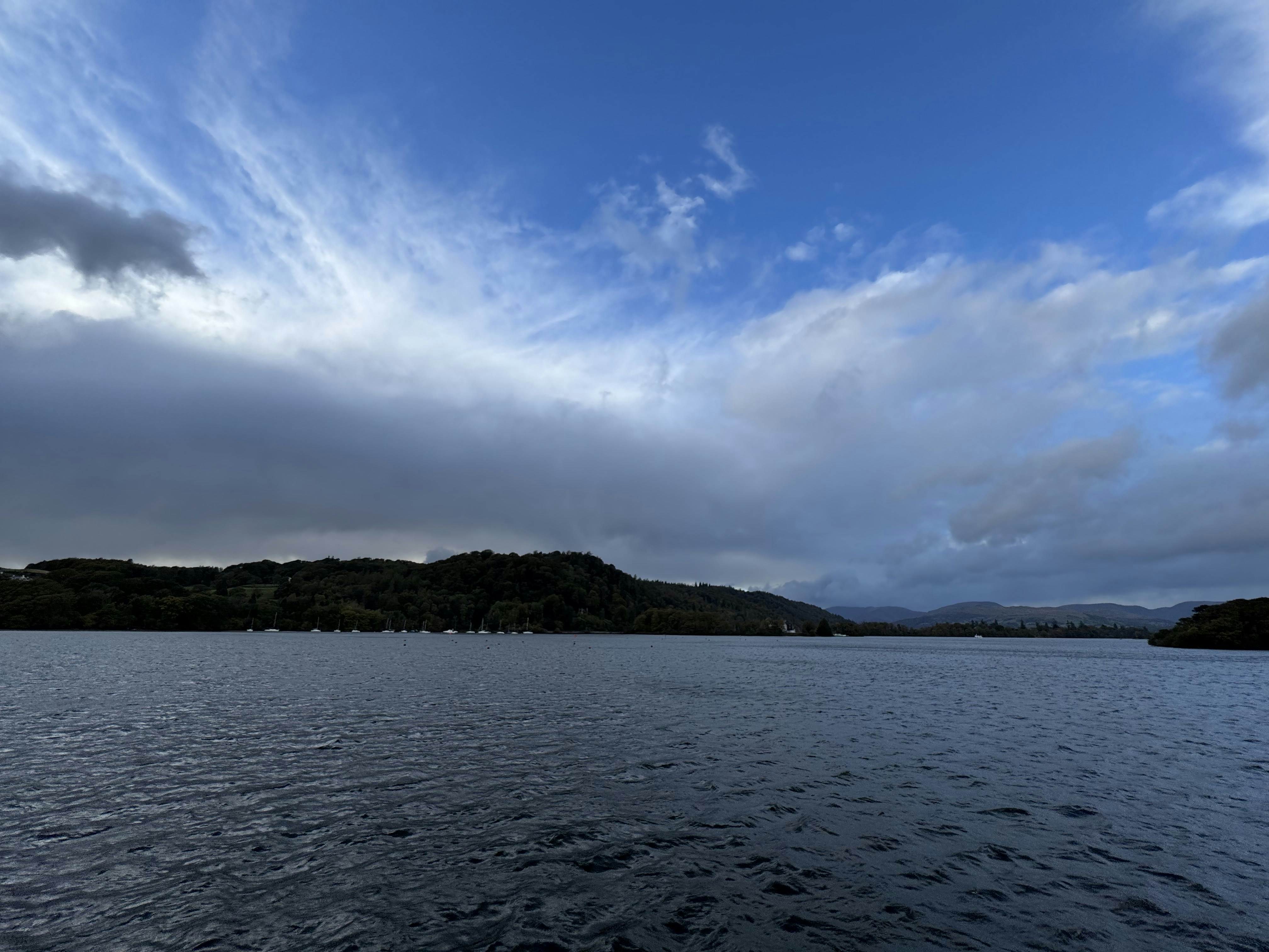 Calm water under a cloudy sky with distant hills