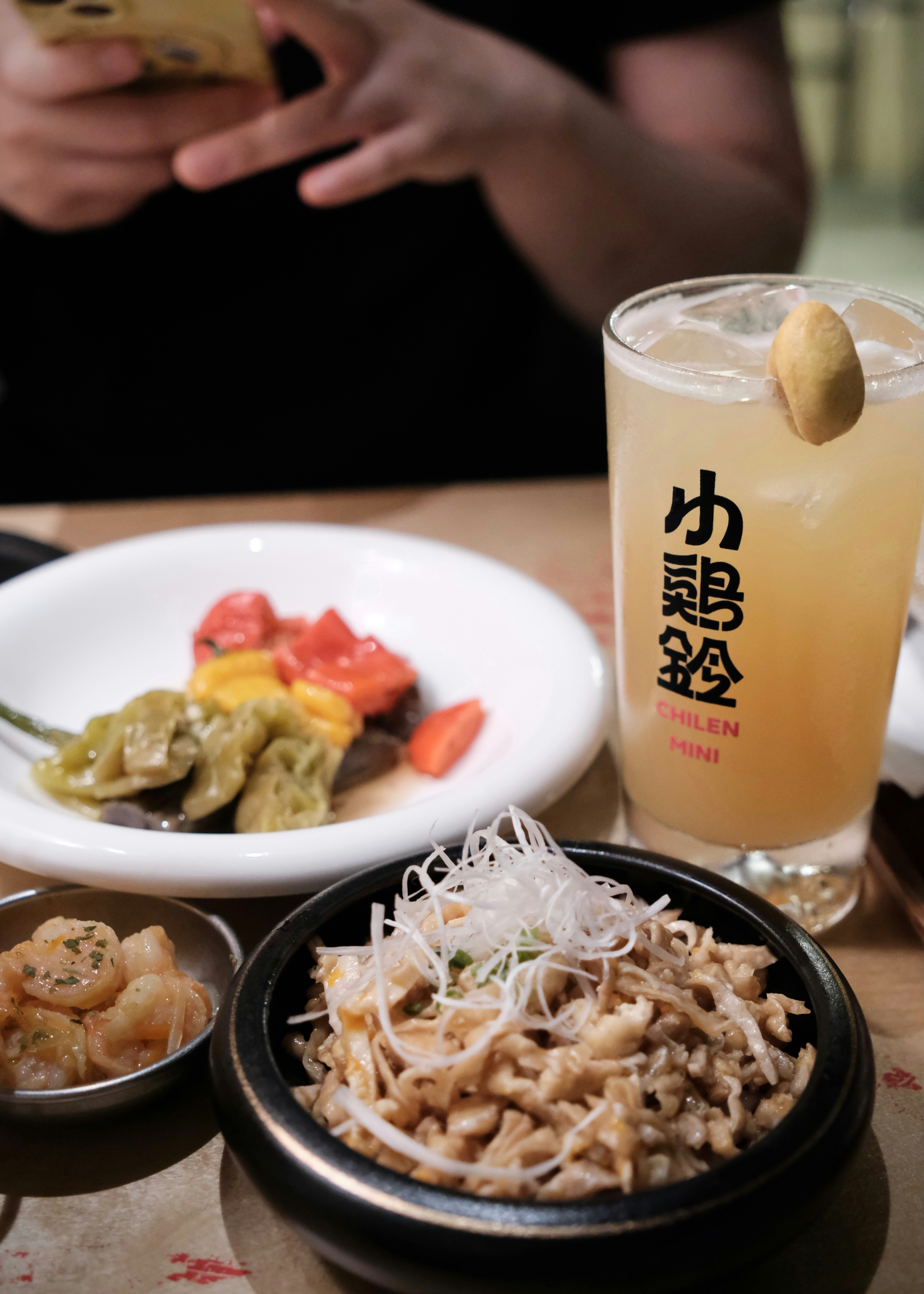 Colorful assortment of dishes featuring vibrant vegetables, a savory bowl of noodles, and a refreshing drink with unique branding.