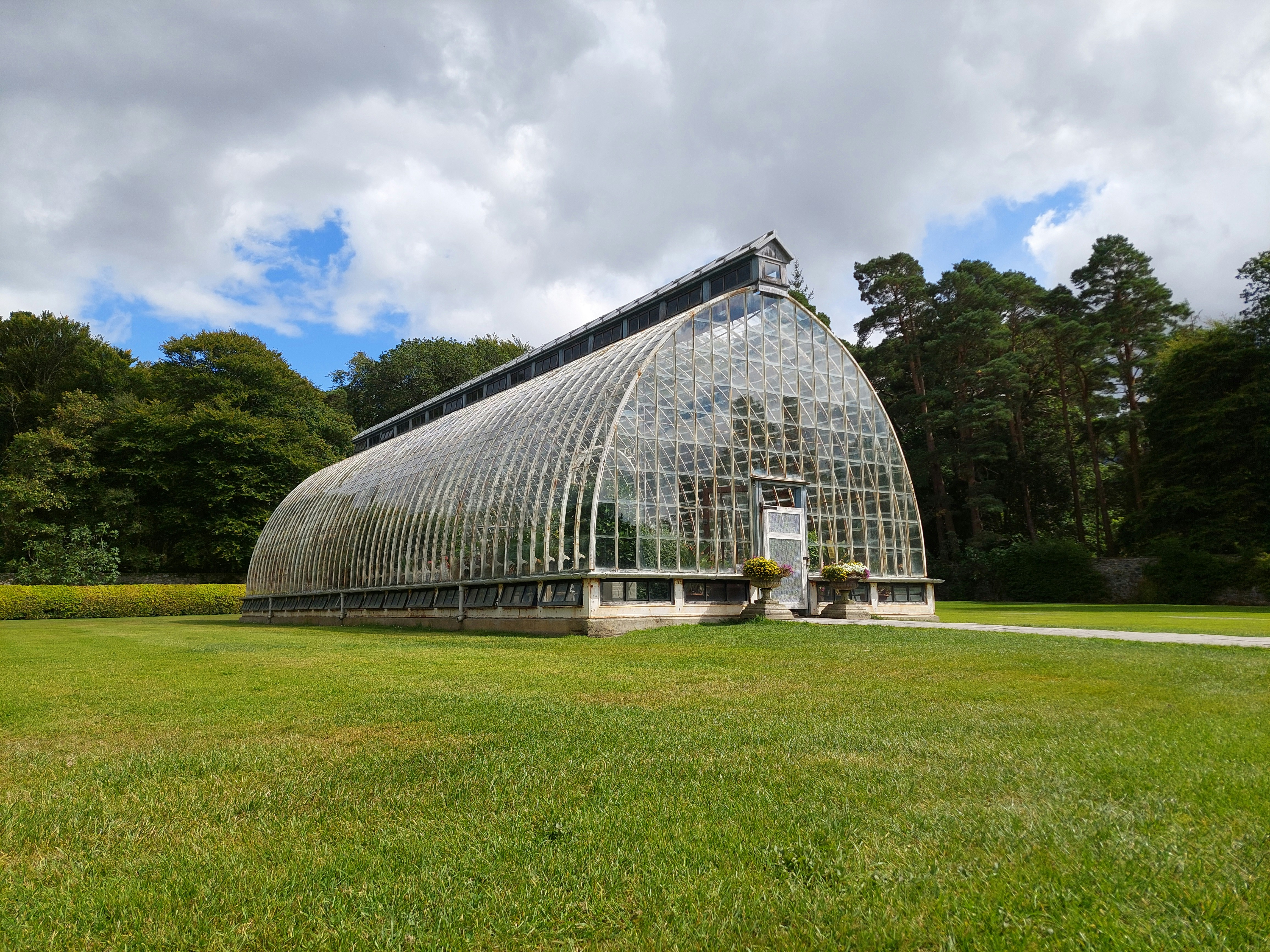 Large greenhouse structure in a grassy park setting.