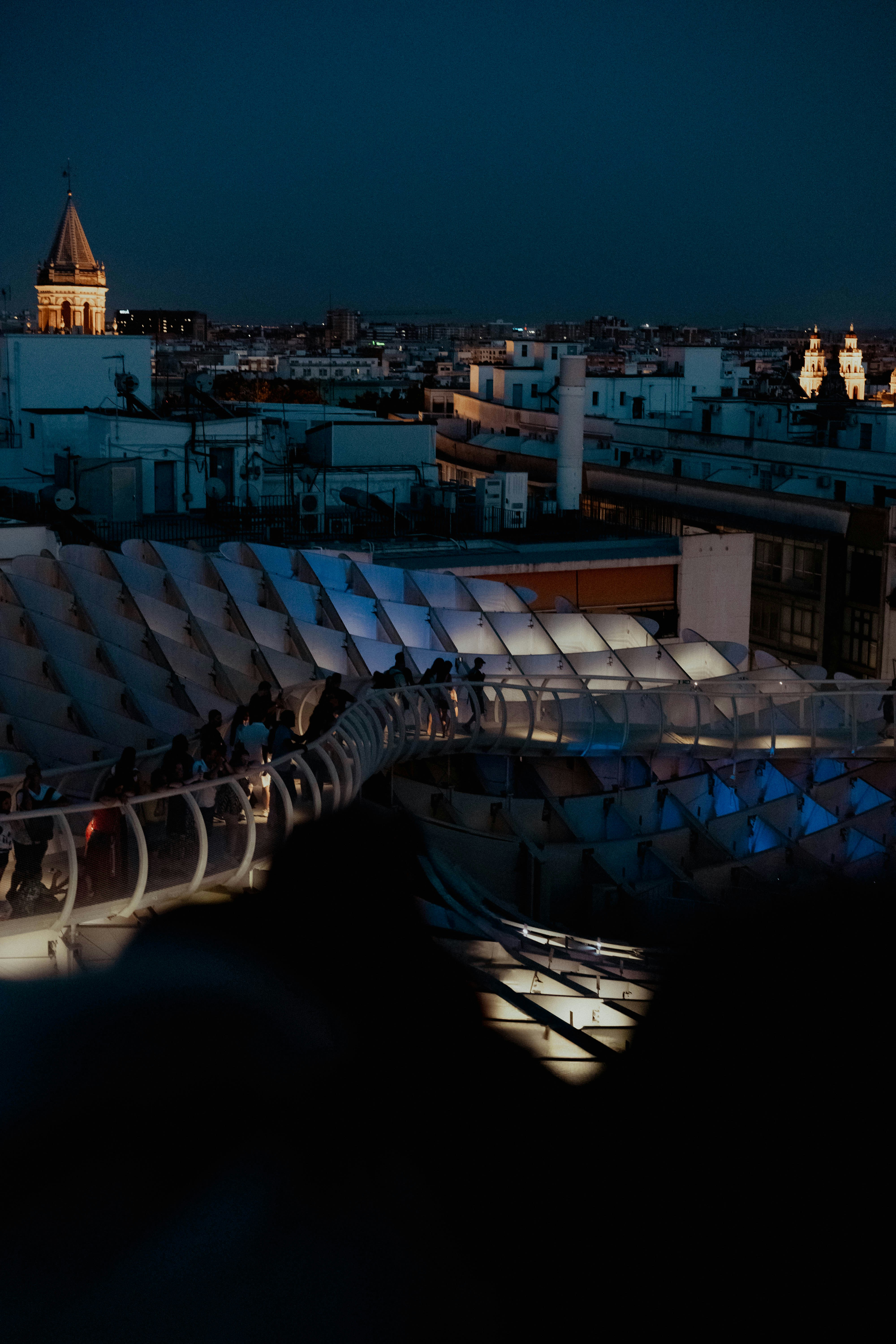 Night Walkway Over a City Silhouette: Curved Glass Canopy Illumination