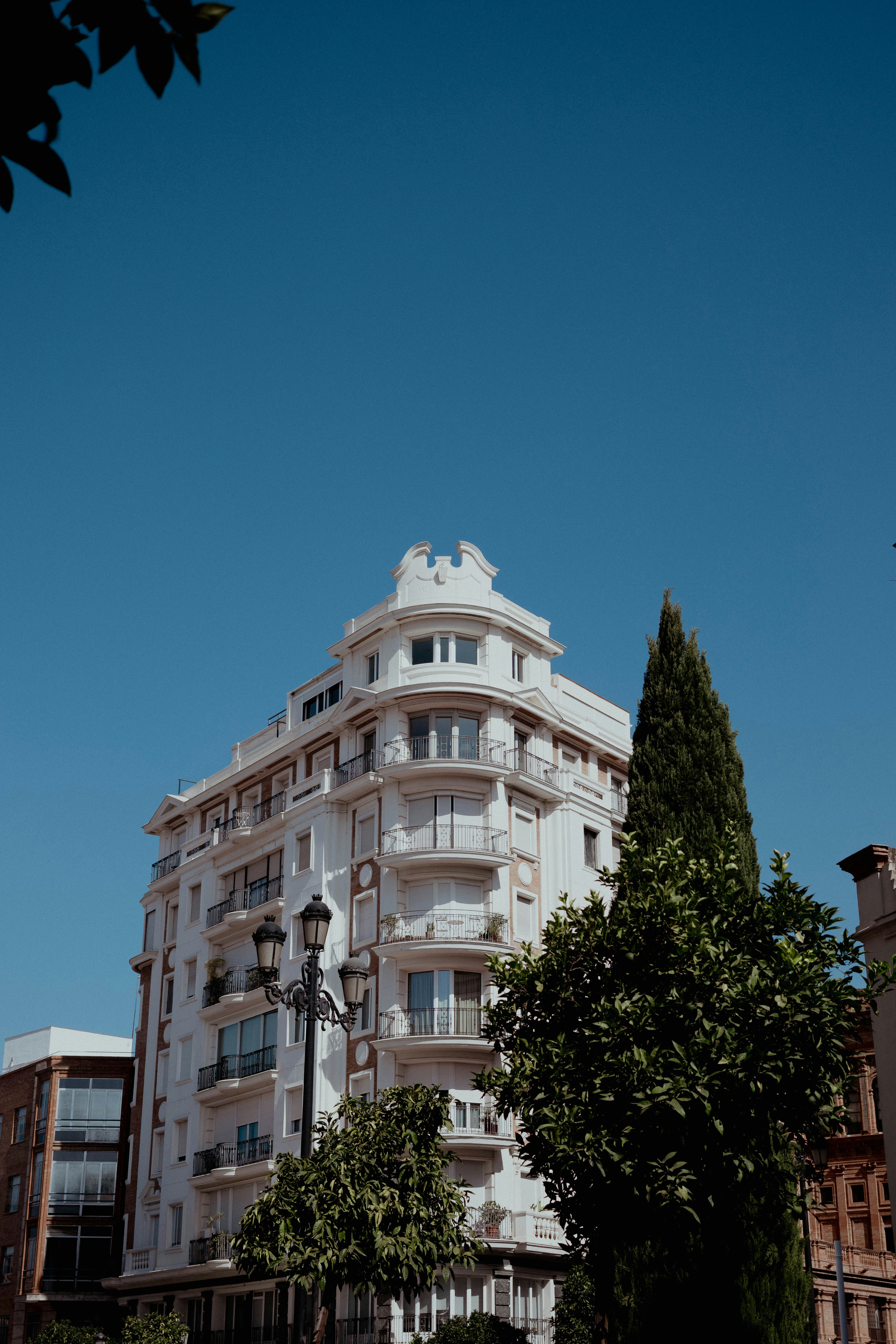 White building with rounded balconies under blue sky.
