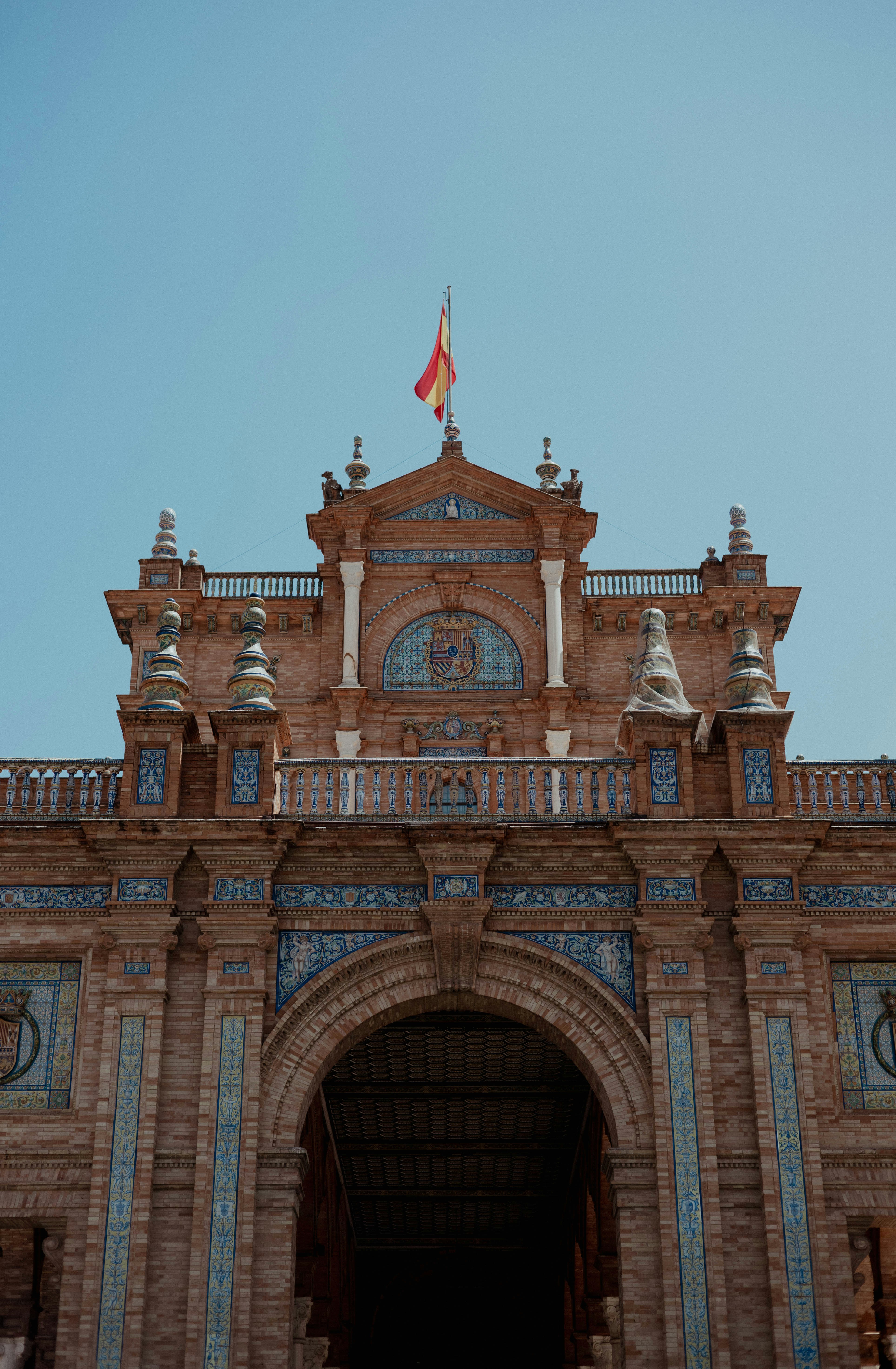 Crown of Tiles: A Flag-Topped Brick Gateway Under a Cerulean Sky