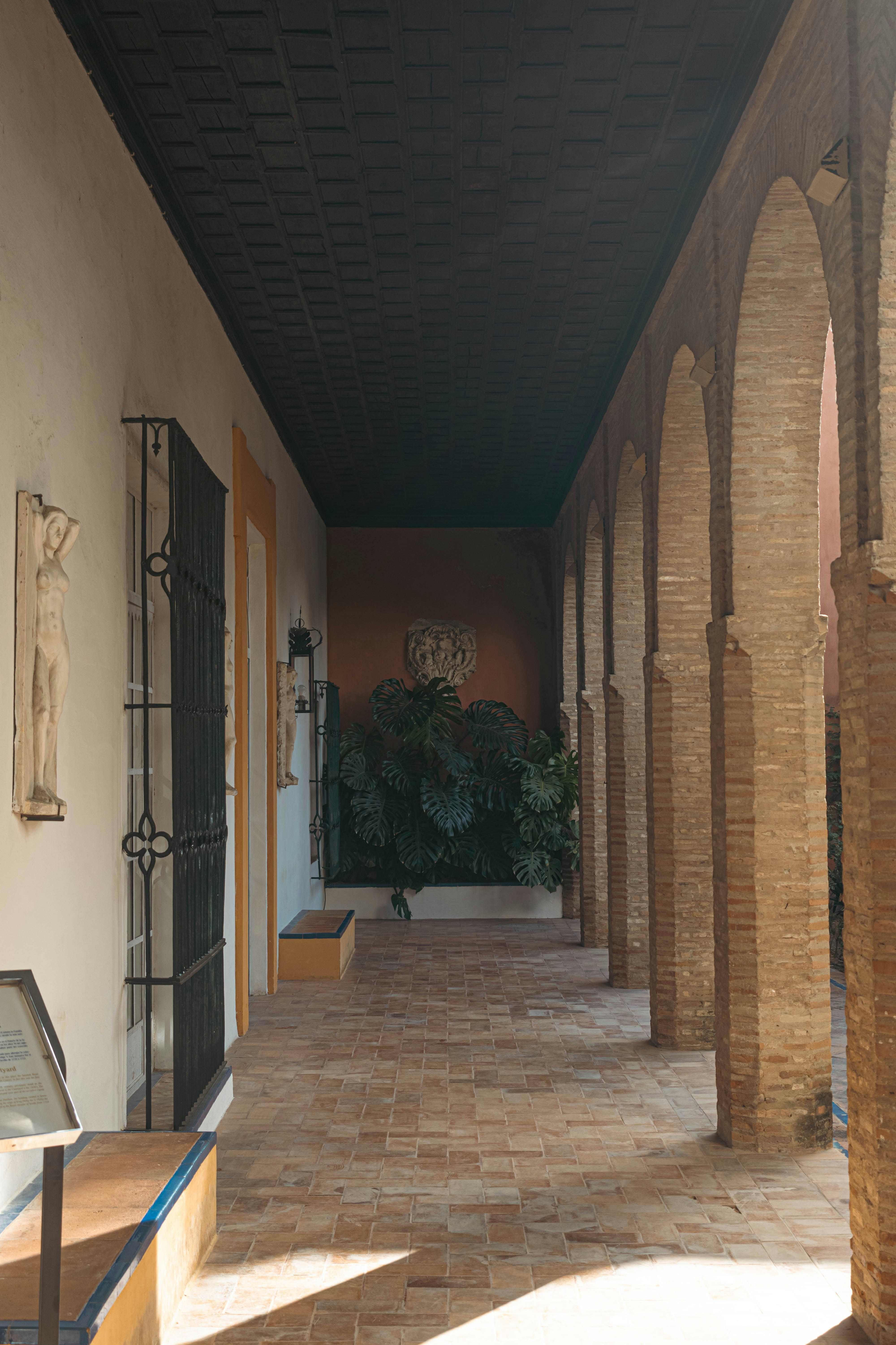 Elegant corridor adorned with arches and sculptures, featuring lush greenery that adds a touch of nature to the architectural design.
