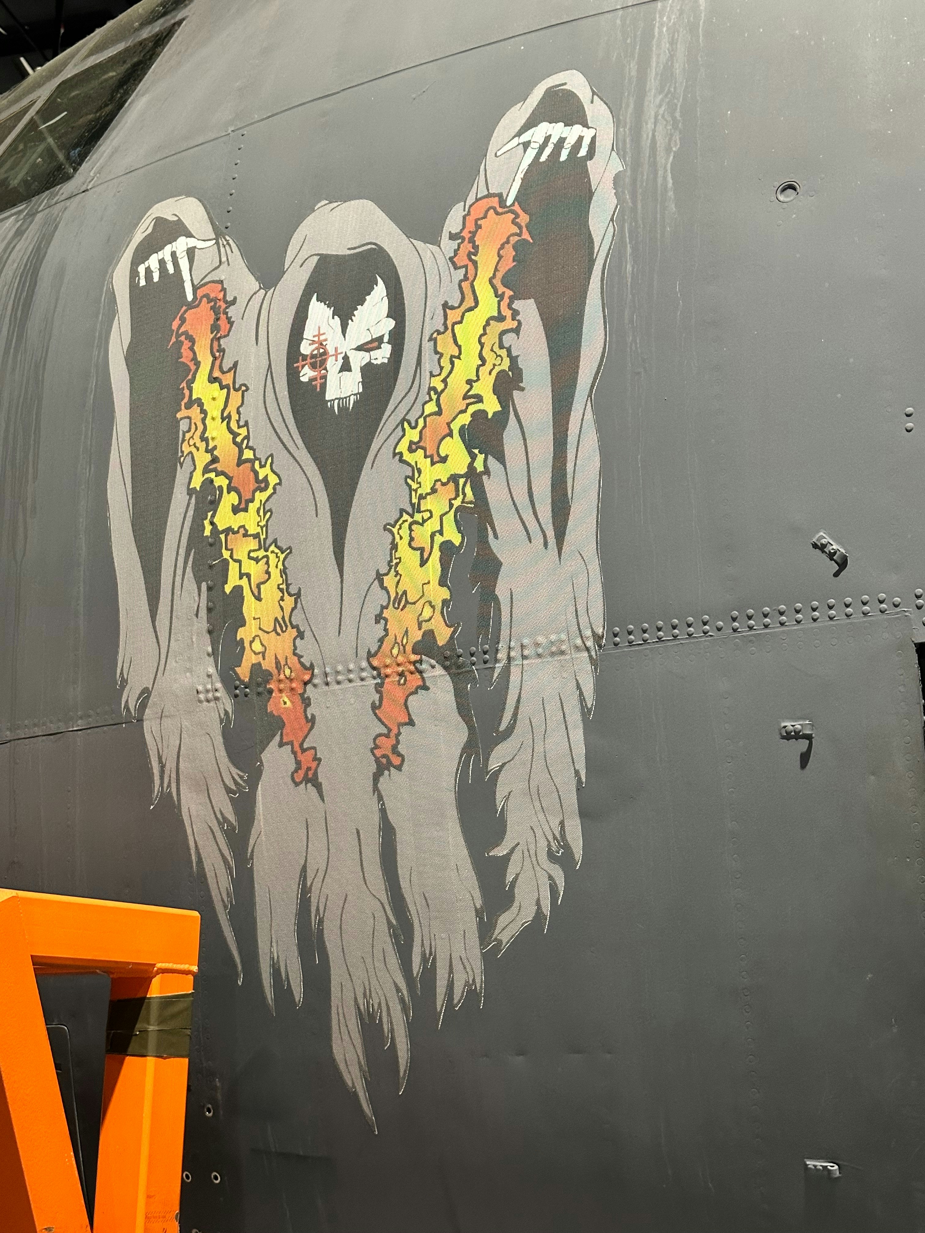 Intricate artwork depicting a ghostly figure with vivid flames on the side of an aircraft. The design merges elements of mystique and power.