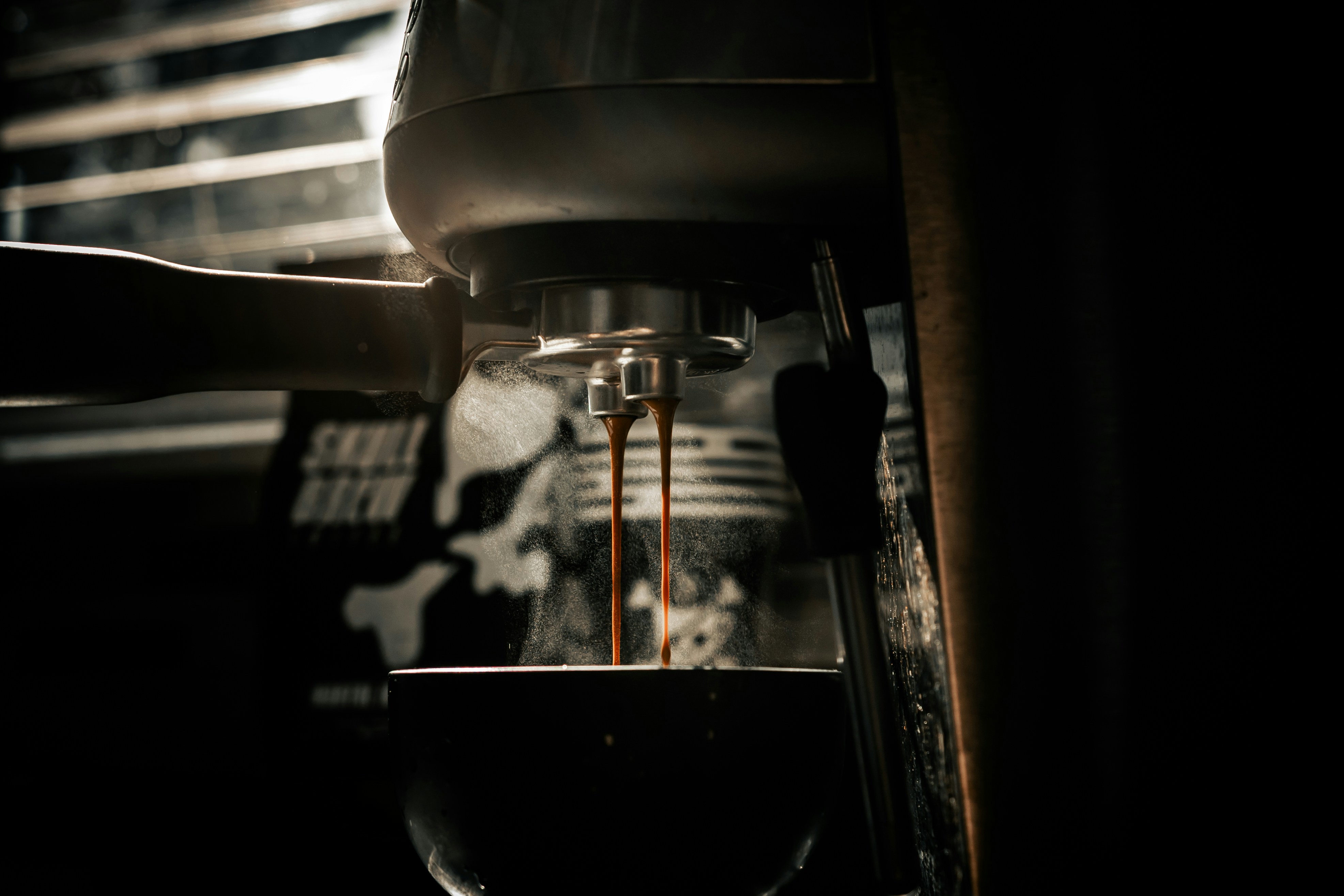 Espresso machine brewing dark coffee into glass.