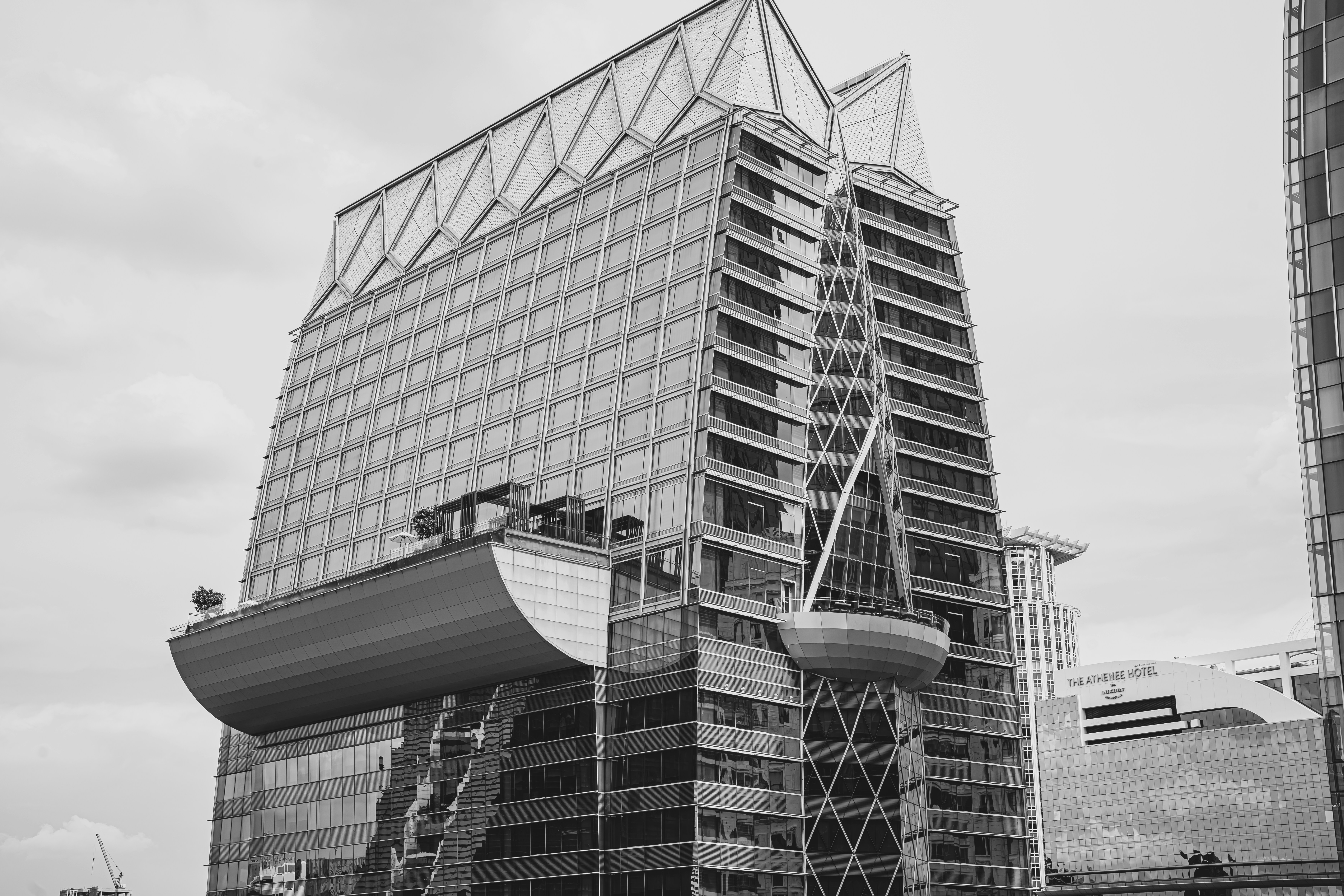 Modern skyscraper with unique architectural design features against cloudy sky