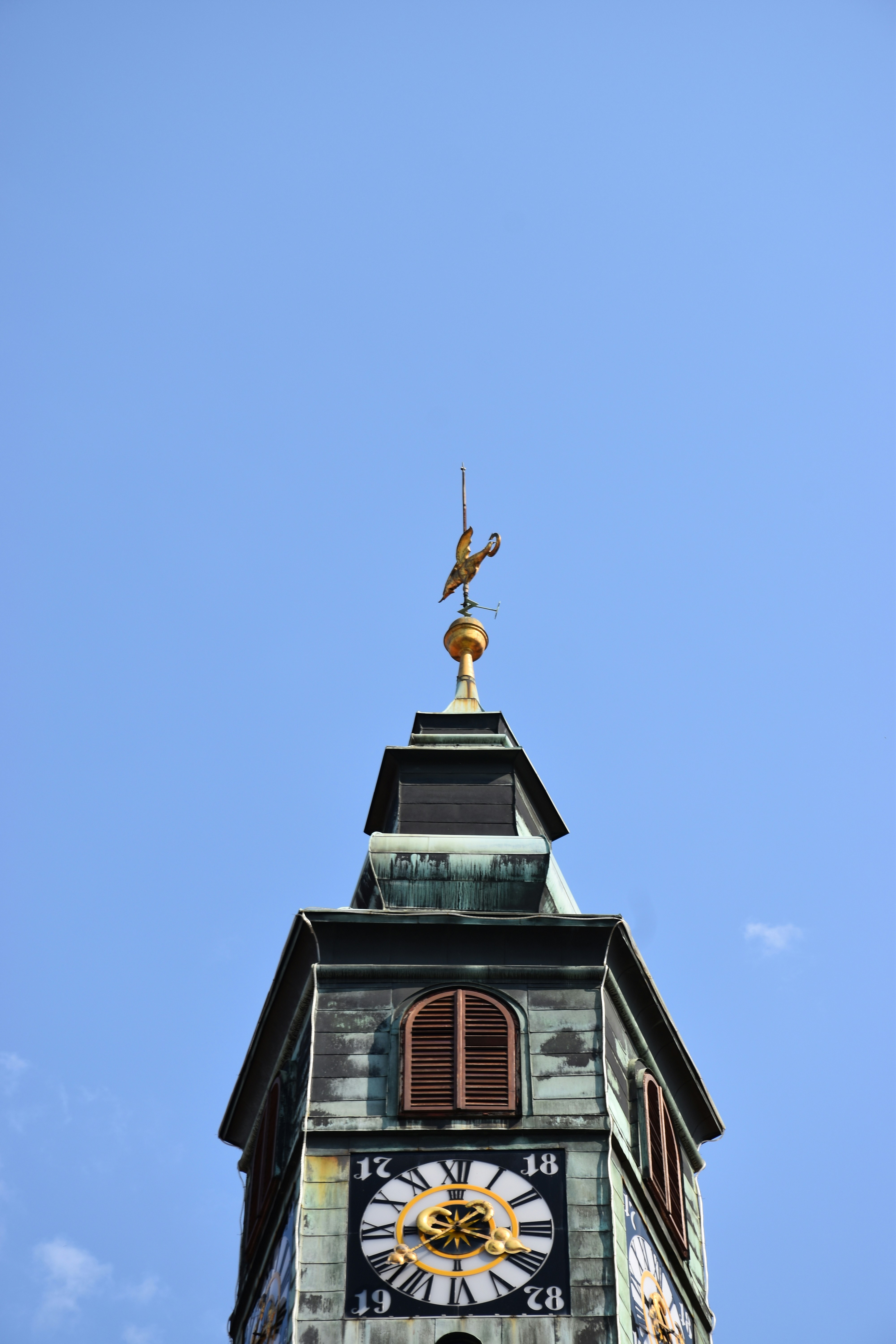 Clock tower with weather vane against clear blue sky