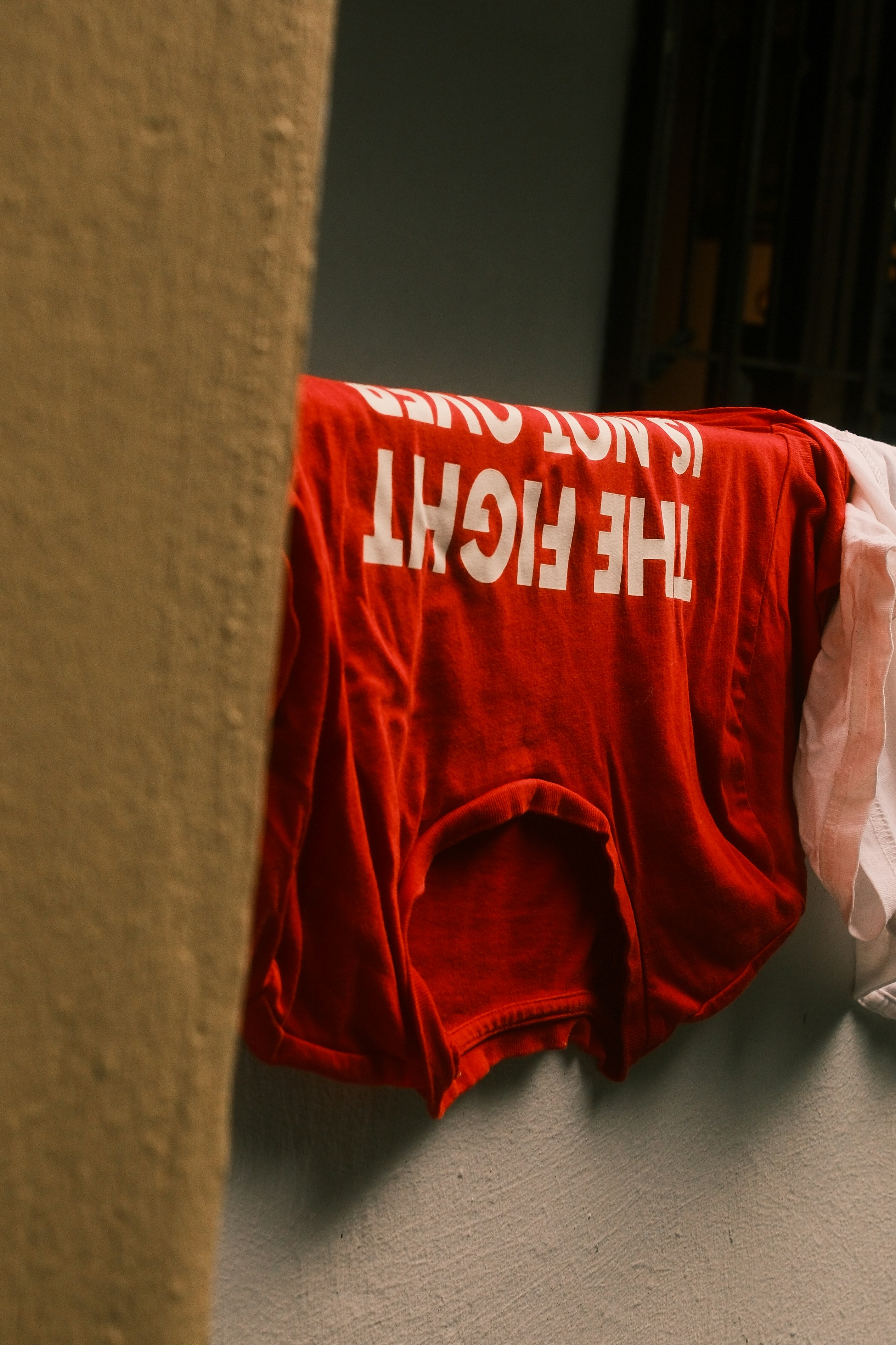 Red t-shirt with white text hangs drying.