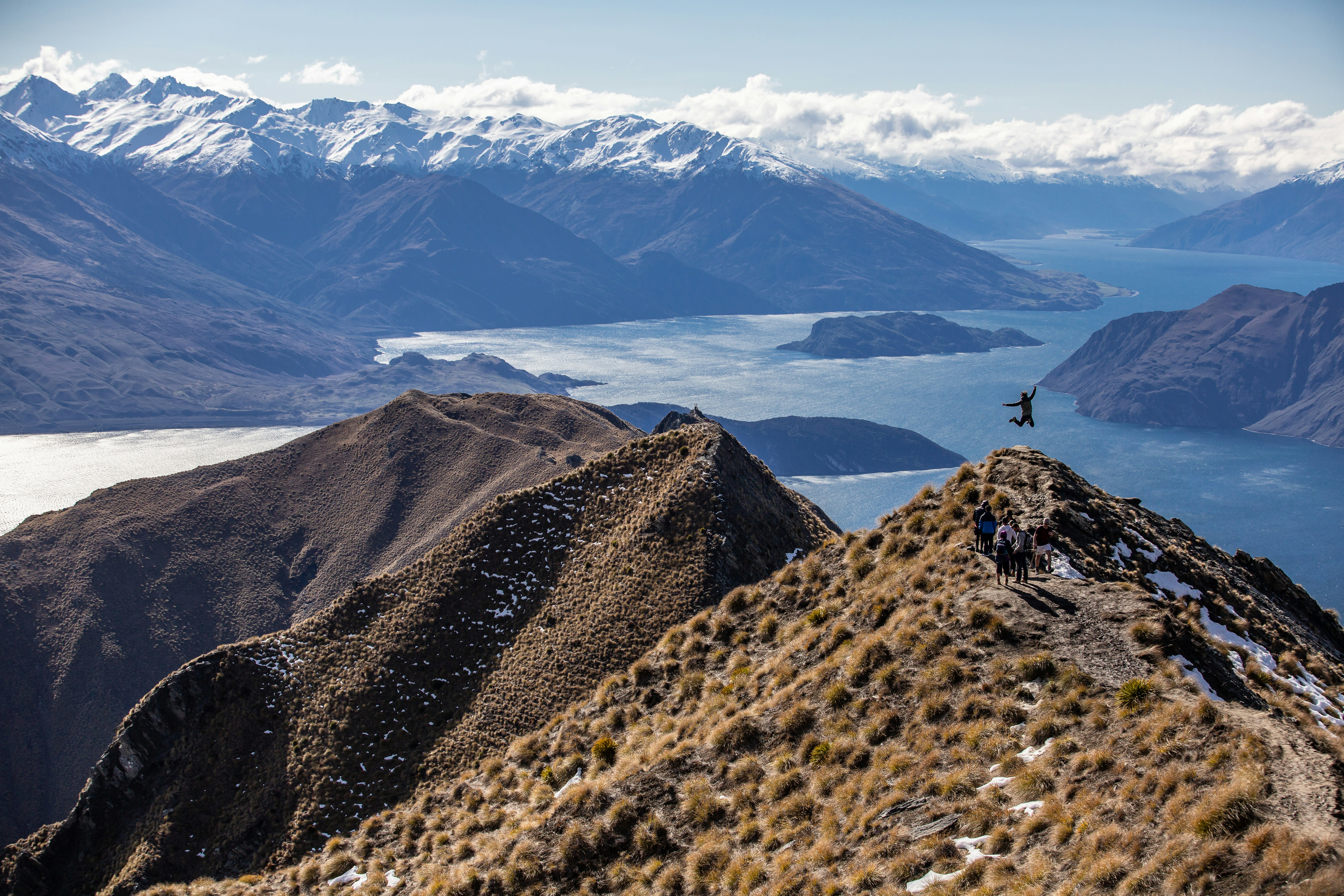 We made it - Roys peak, Wanaka | A lone hiker stands on a mountain ridge overlooking a lake.