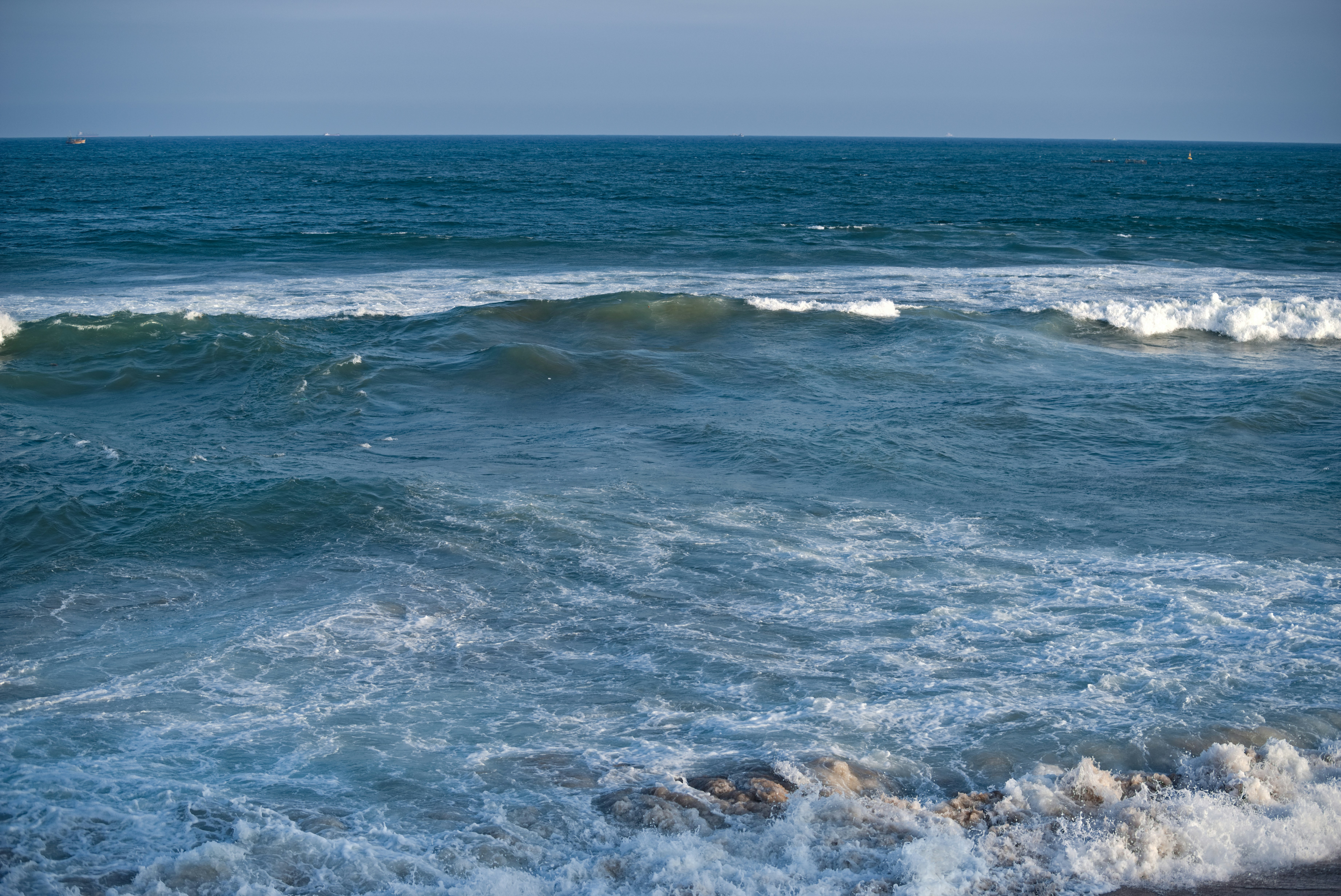 Waves crashing on a sandy beach under a clear sky