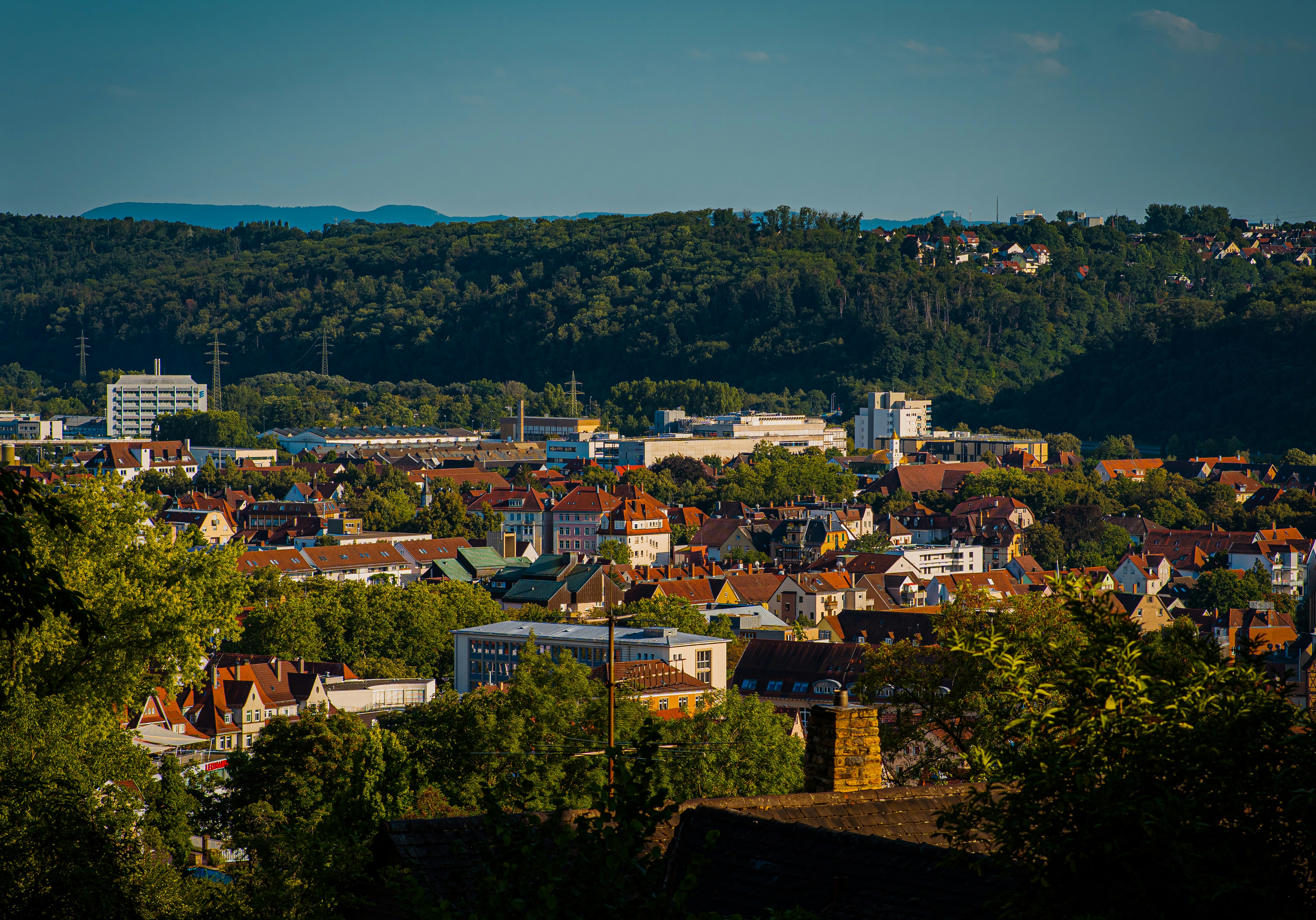 Cityscape with buildings nestled among trees and hills.