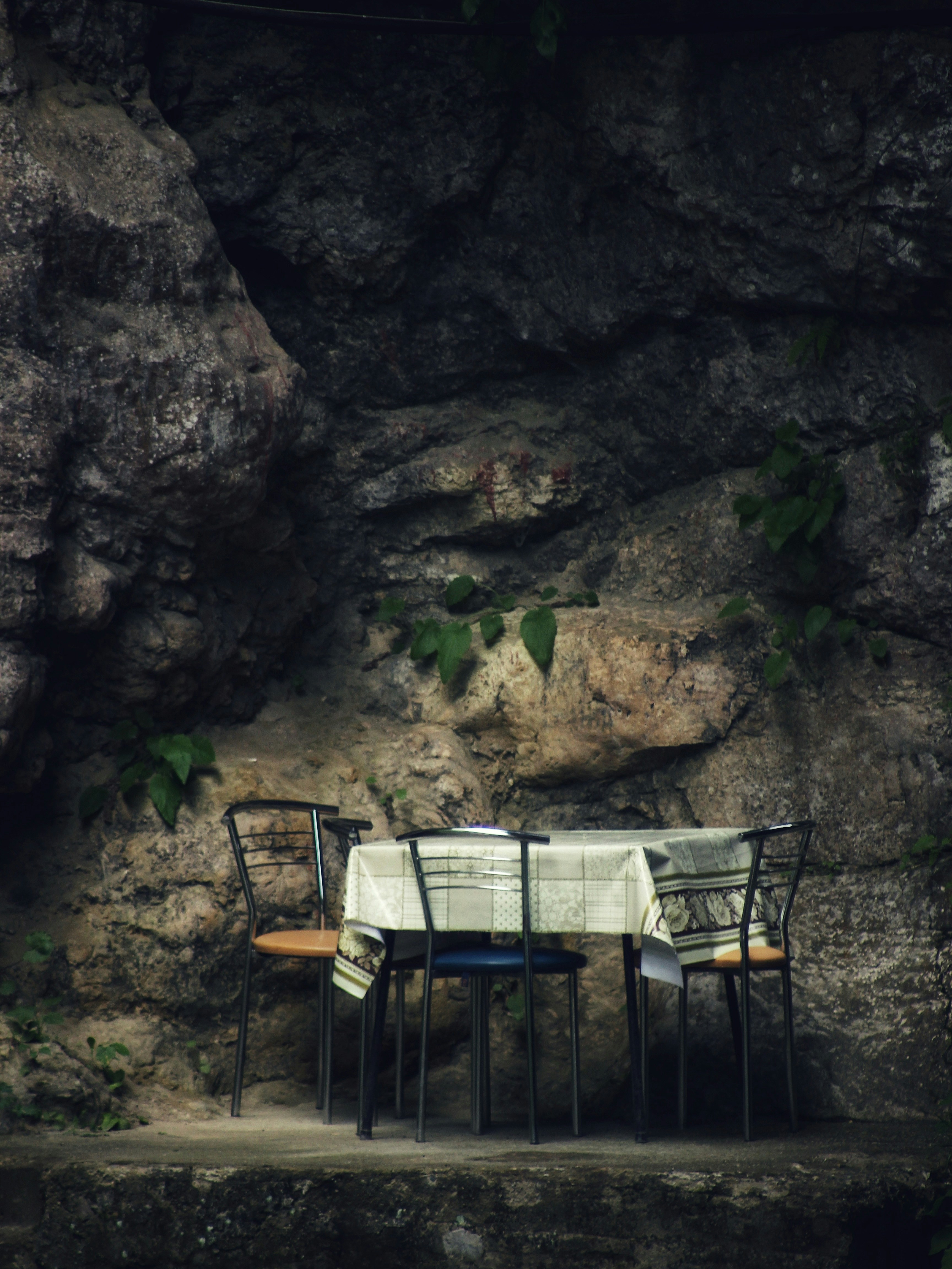 Table and chairs set against a rocky cliff face