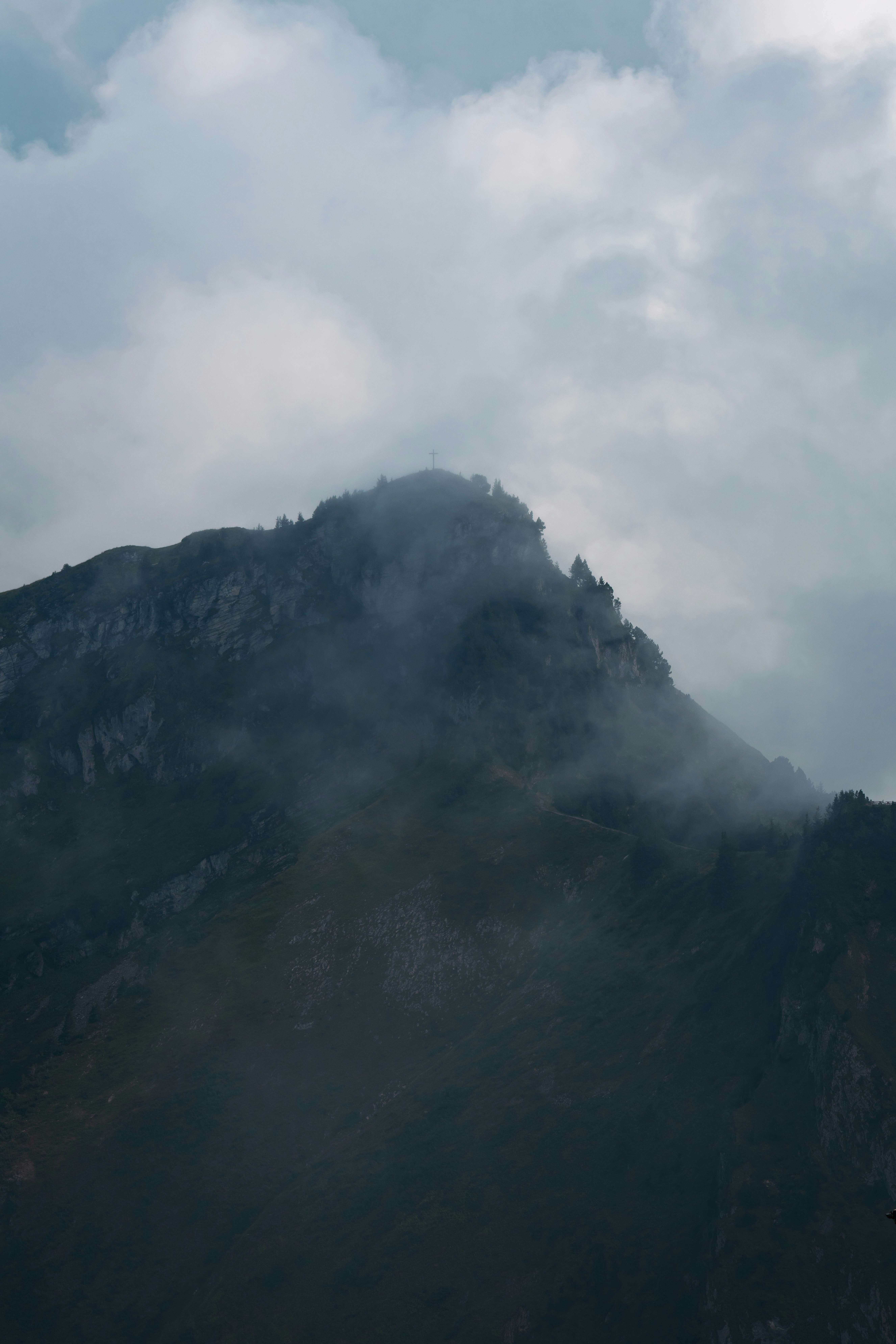 Misty mountain peak partially obscured by clouds, hinting at hidden trails and adventures. The rugged terrain contrasts with the ethereal atmosphere.