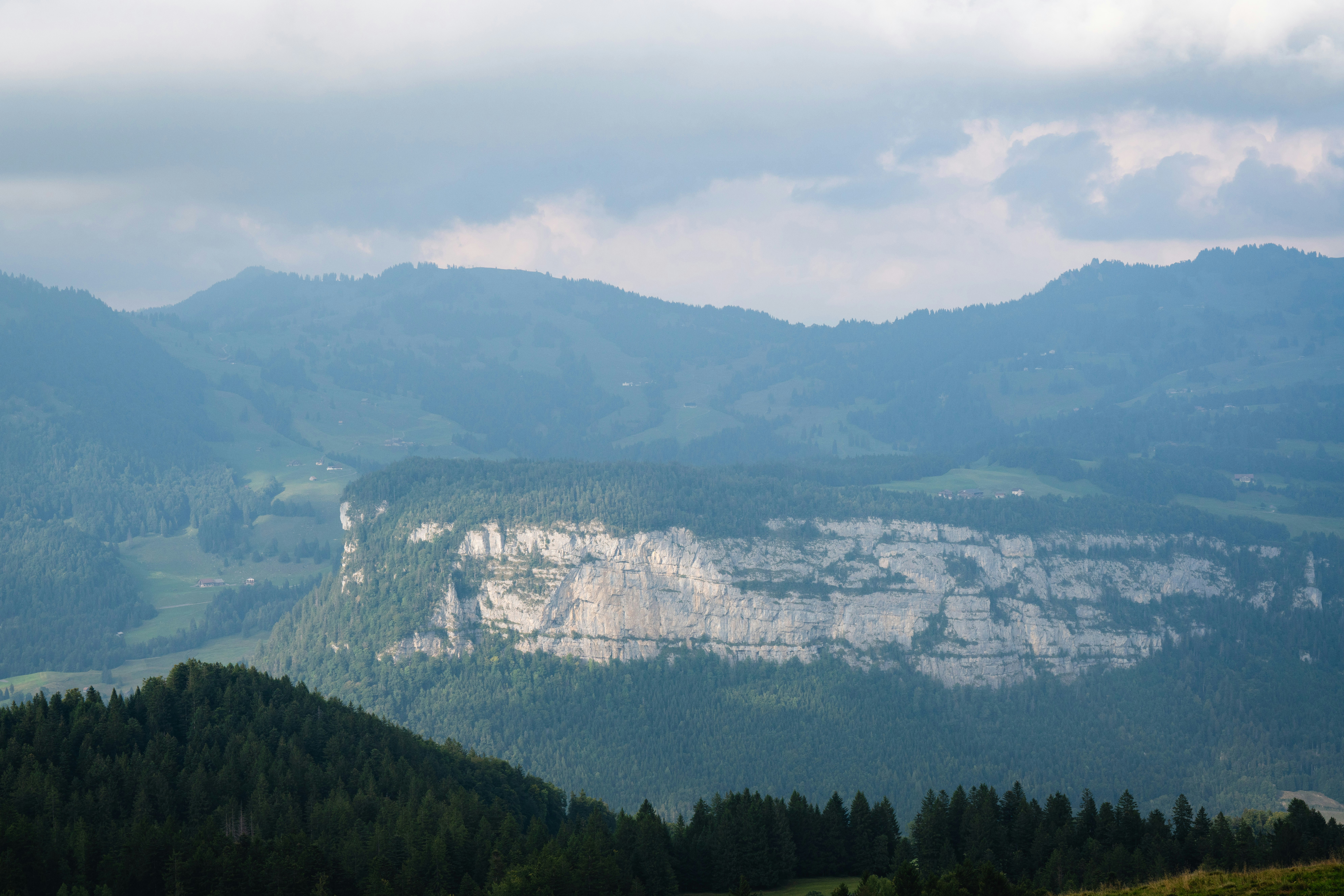 Layered cliffs rise above a green forested valley