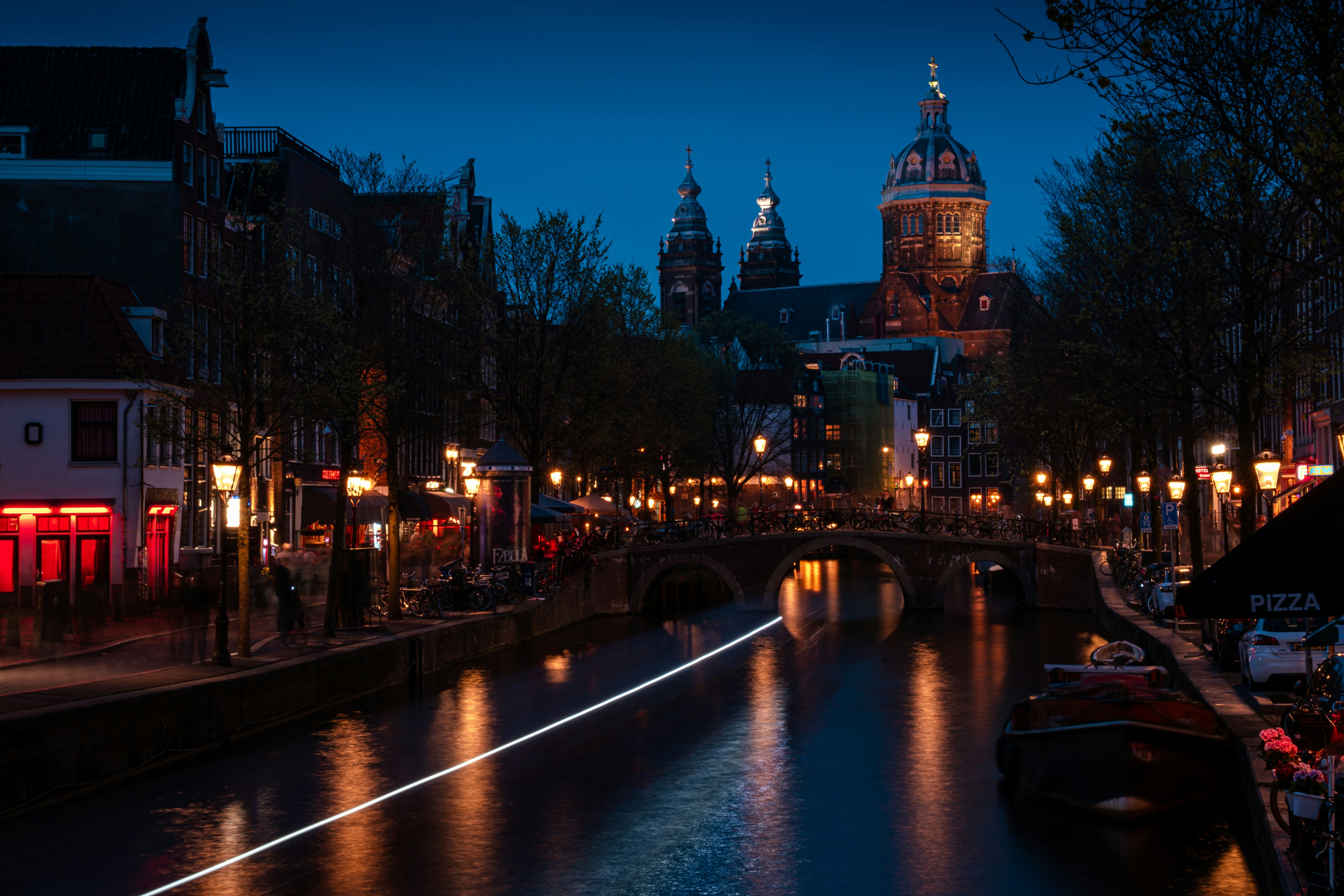 Canal in amsterdam at night with illuminated buildings