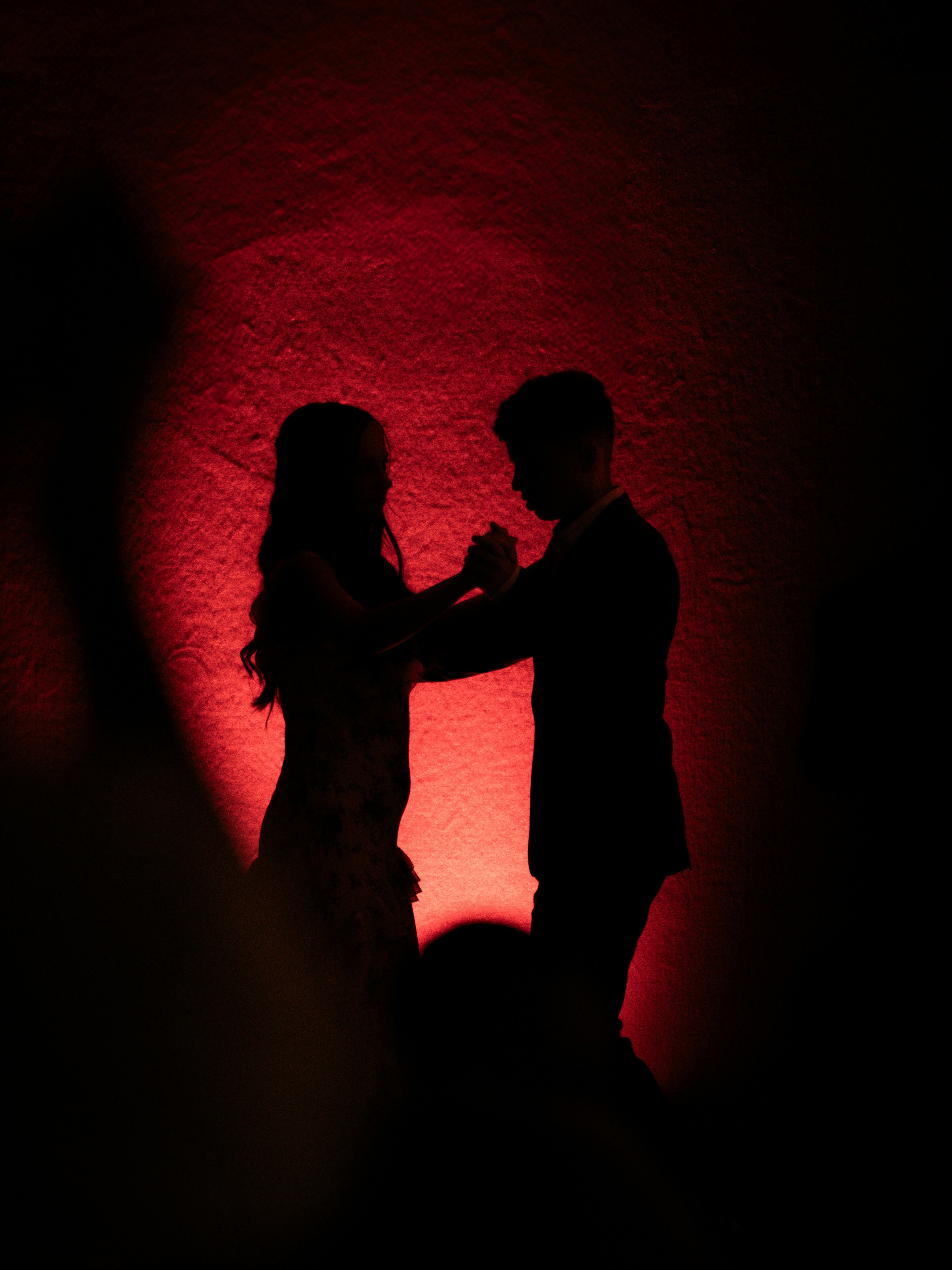 Silhouettes of a couple dancing under red light