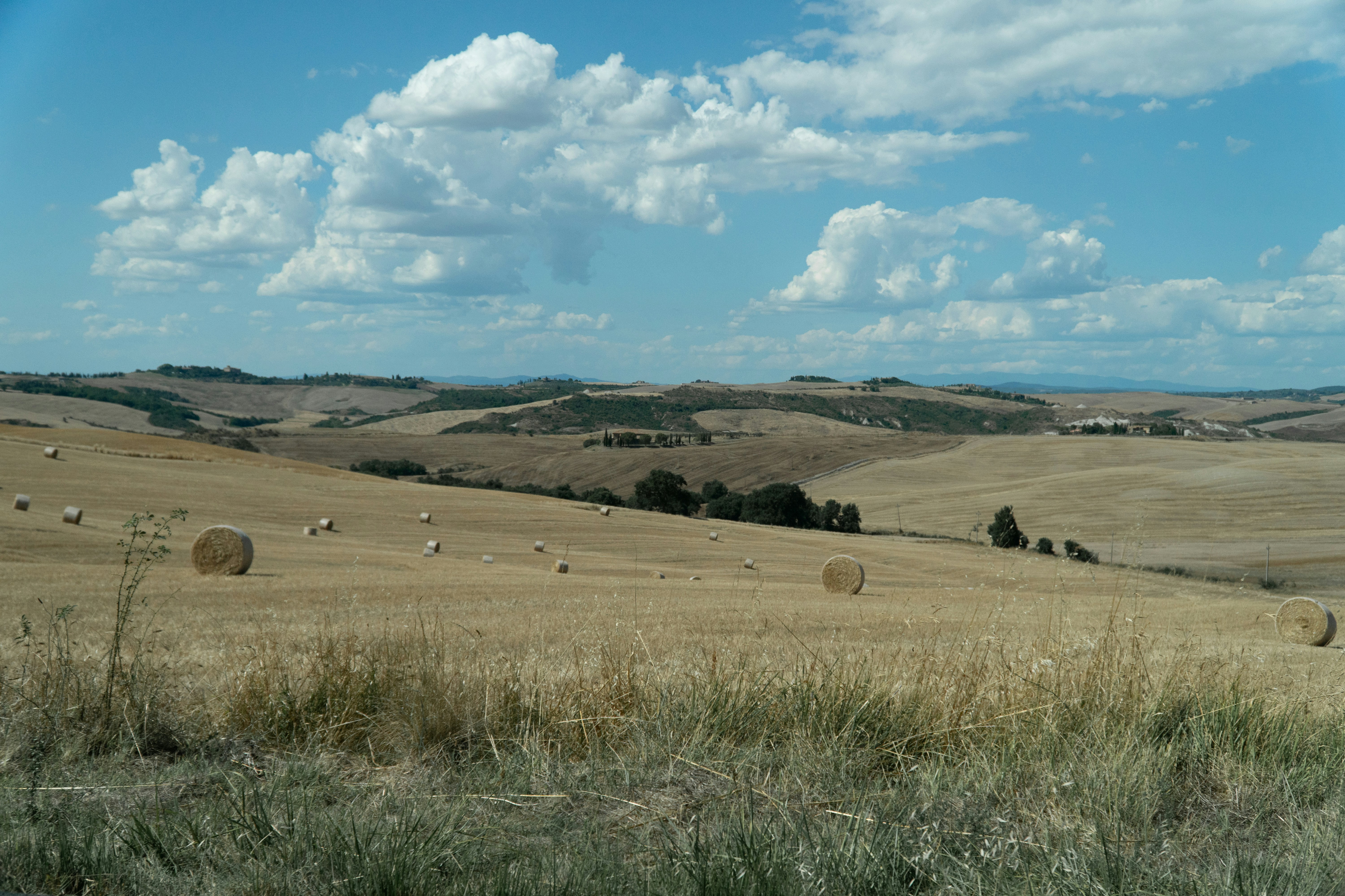 Golden hay bales on a rolling tuscan hillside under clouds