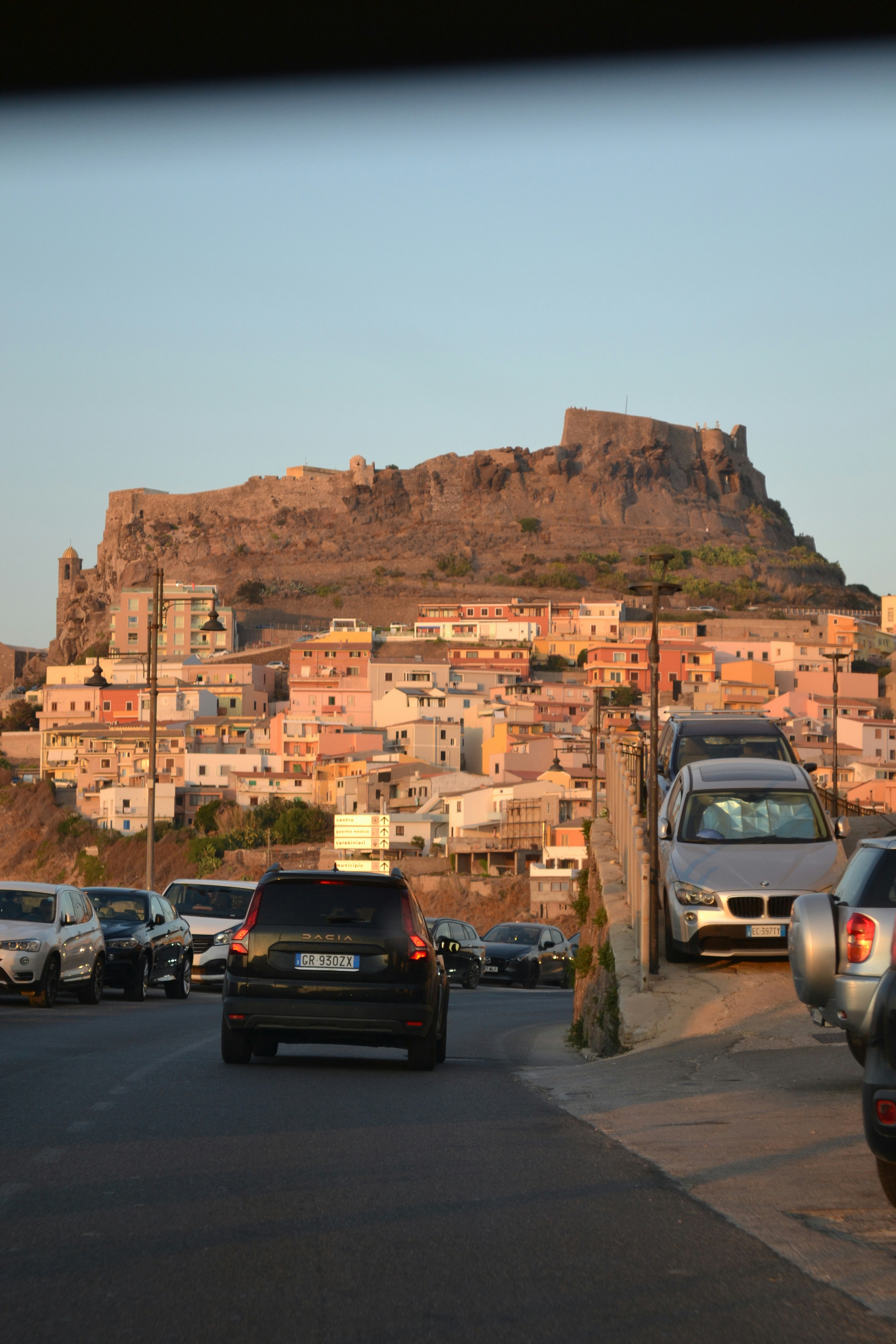 Cars on road with town and castle on hill