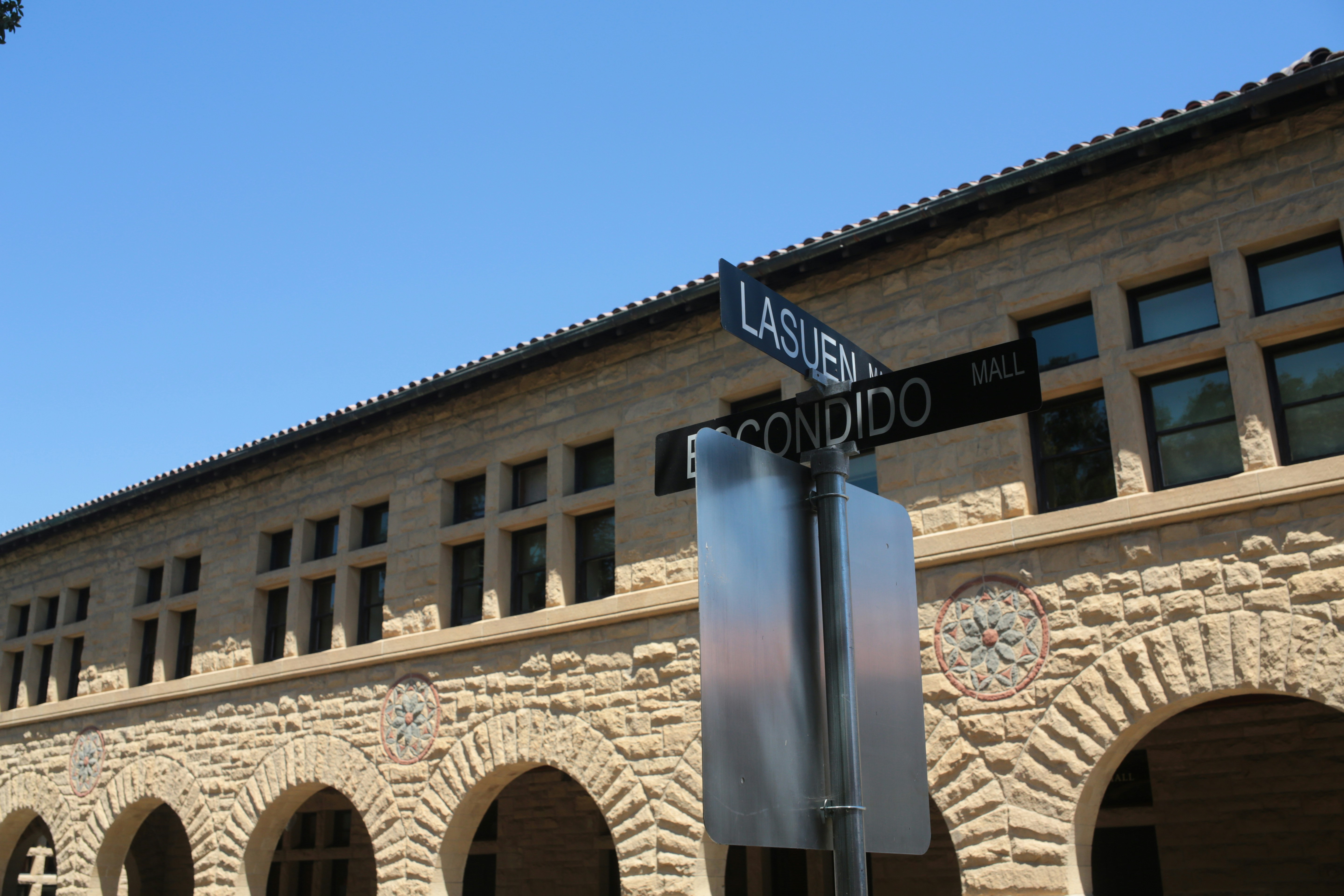 Corner Signpost Framing Sunlit Arches in a Historic Plaza