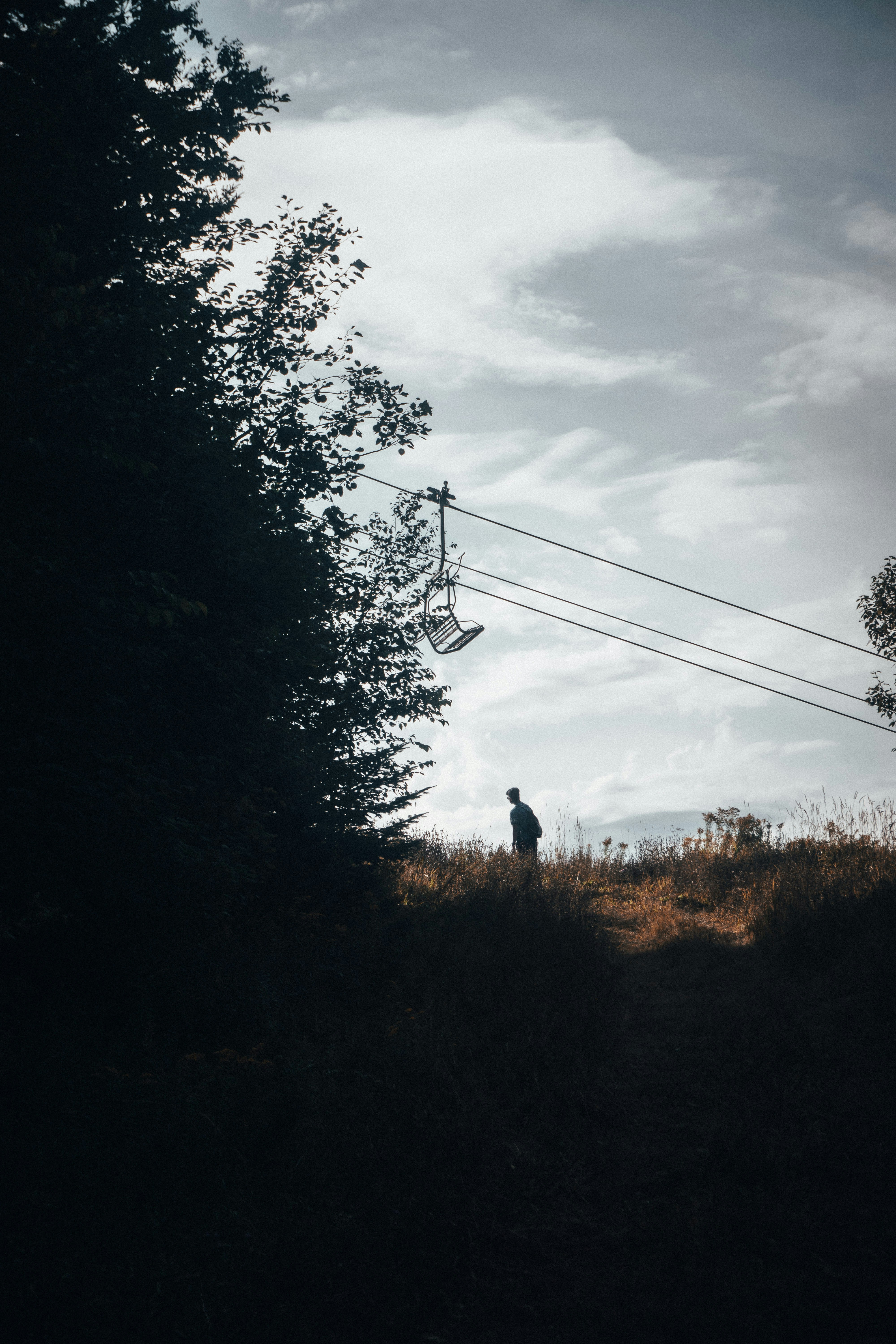 Person walking near ski lift under cloudy sky