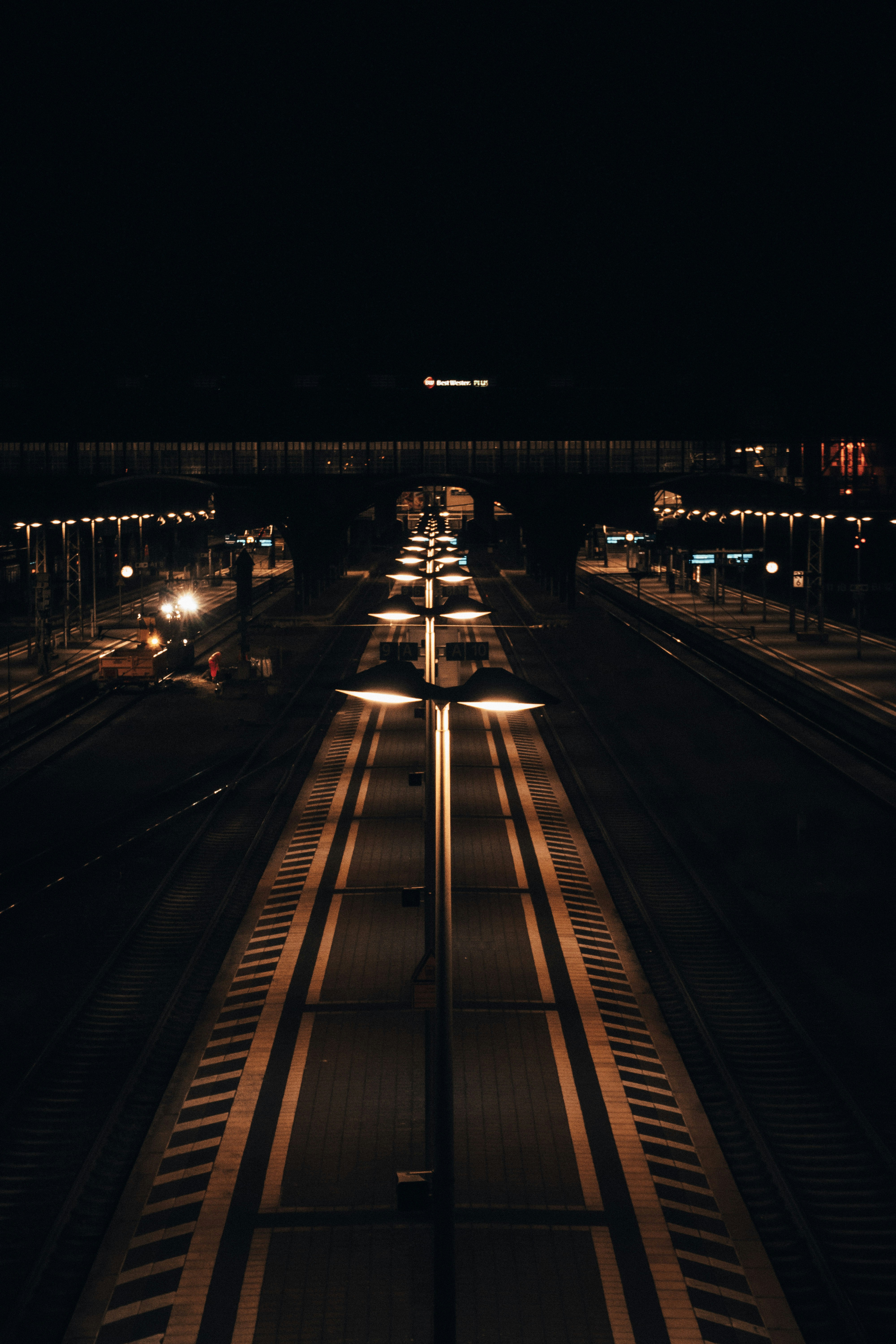 train station at night | Train station platforms illuminated at night with distant building lights