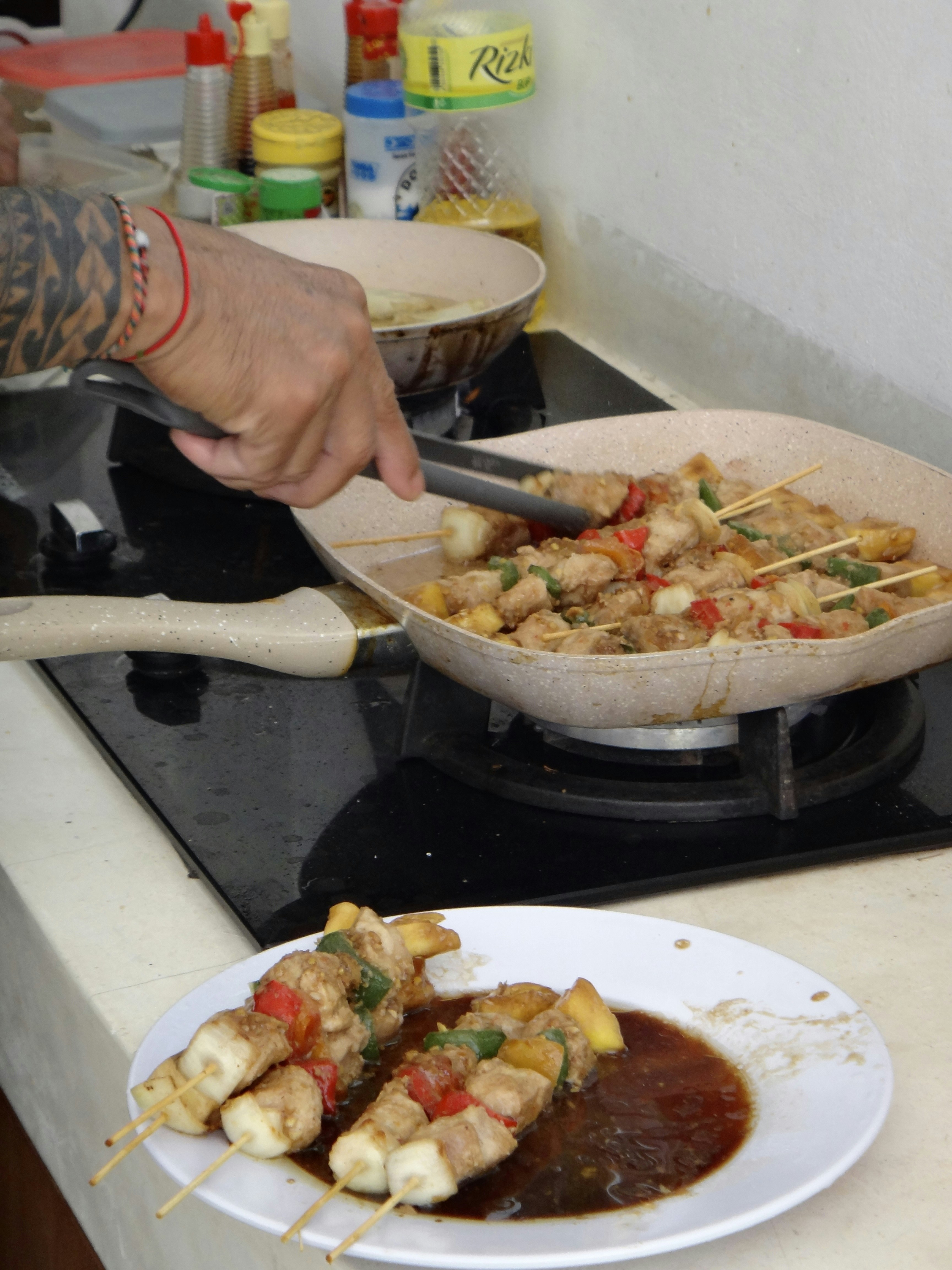 Chef cooking skewers | Person cooking skewers in a pan and on a plate