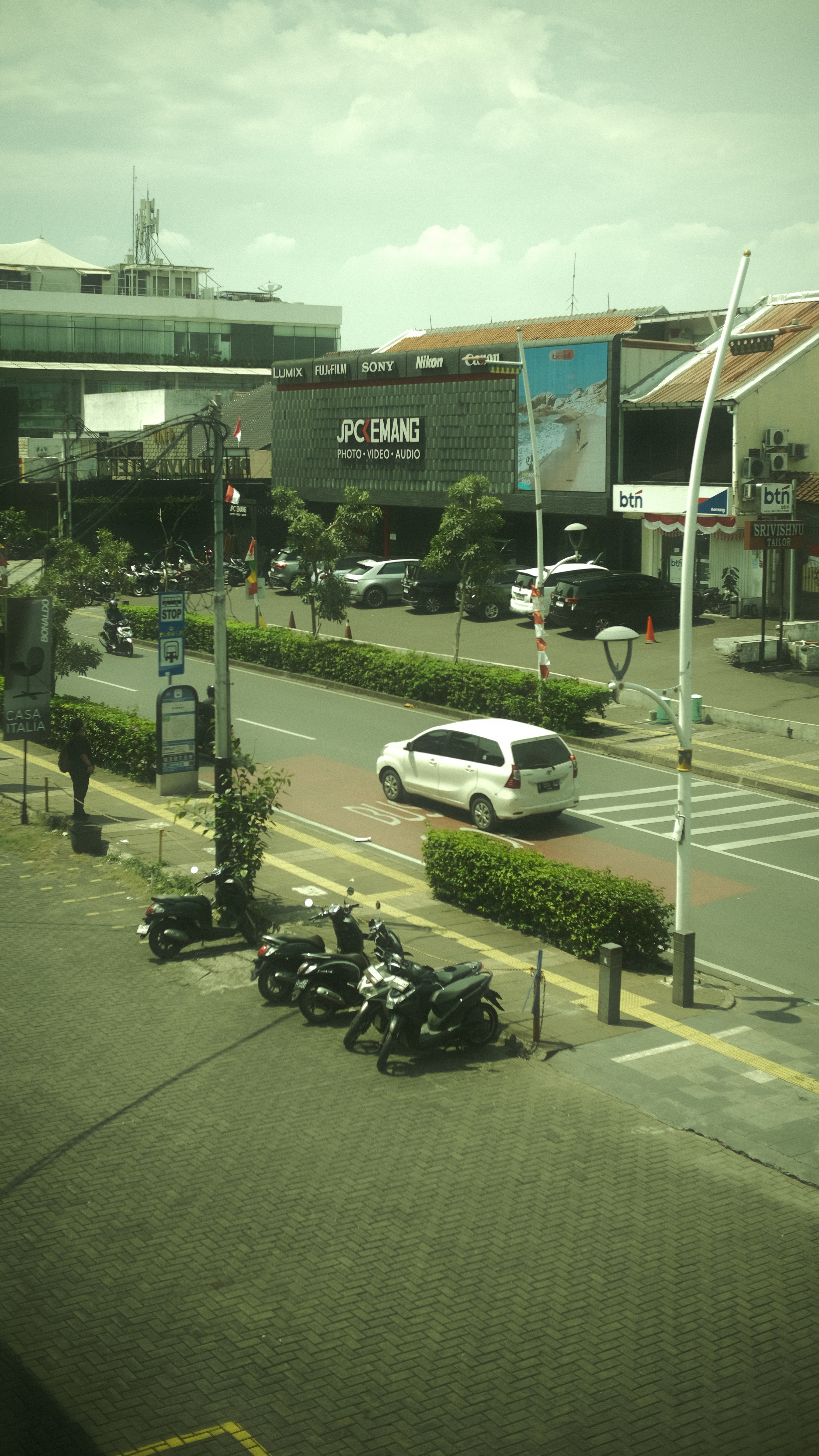 Cars and motorcycles on a city street near buildings.